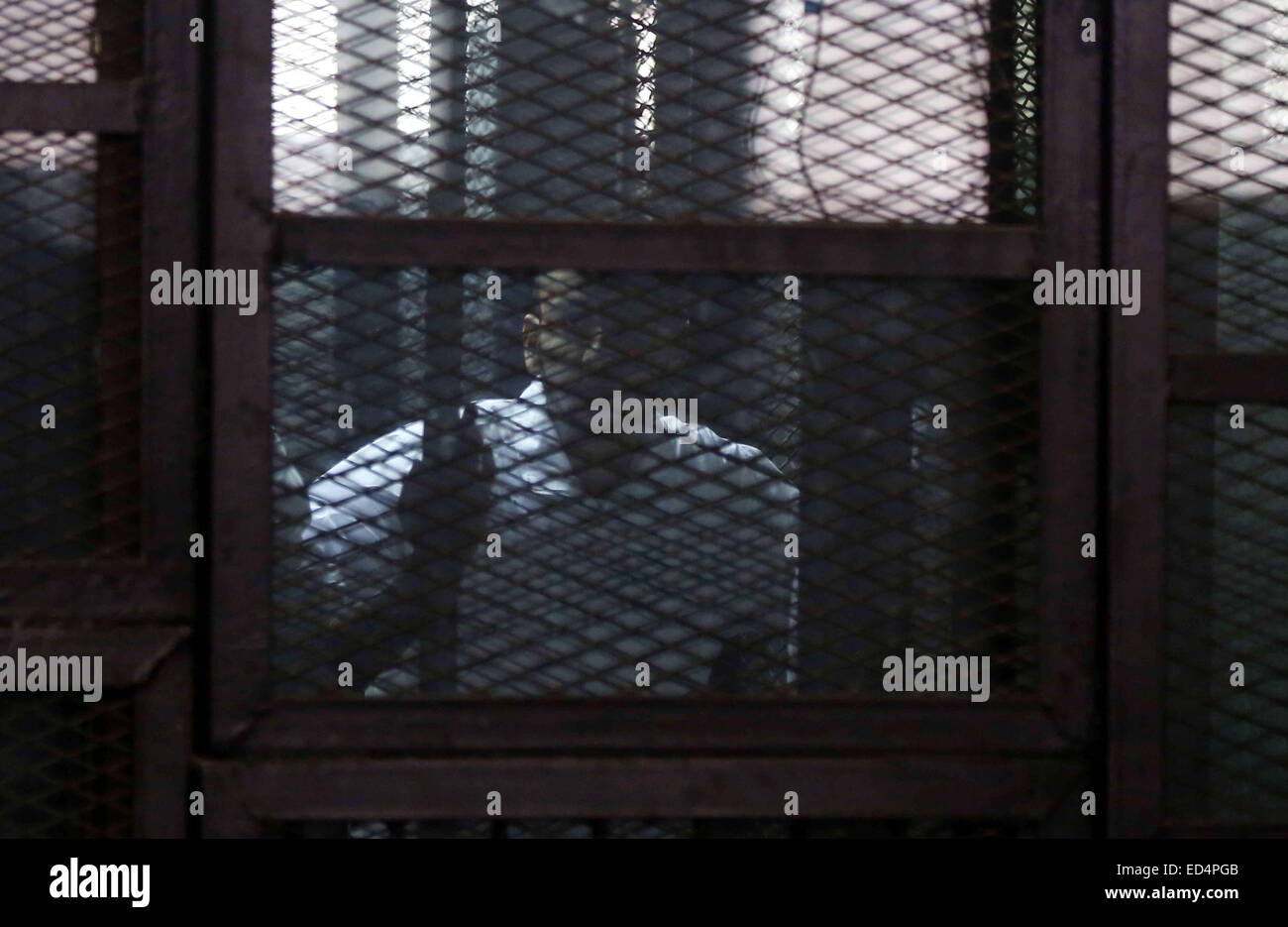 Cairo, Egypt. 25th Dec, 2014. Defendants stand in a courtroom cage ...