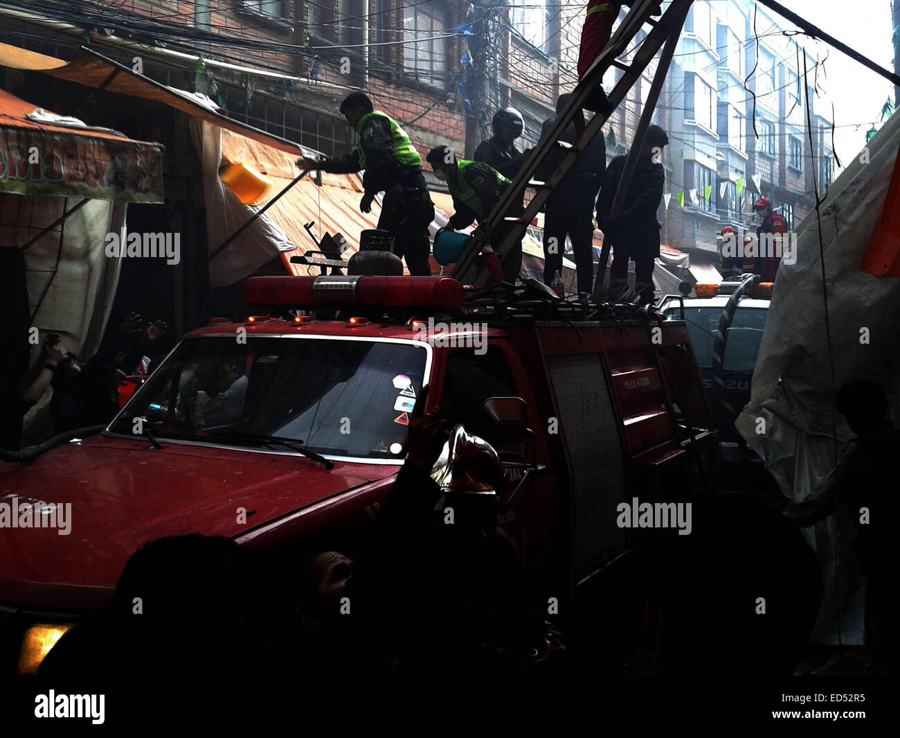 La Paz, Bolivia. 27th Dec, 2014. Firemen work at a building caught on ...