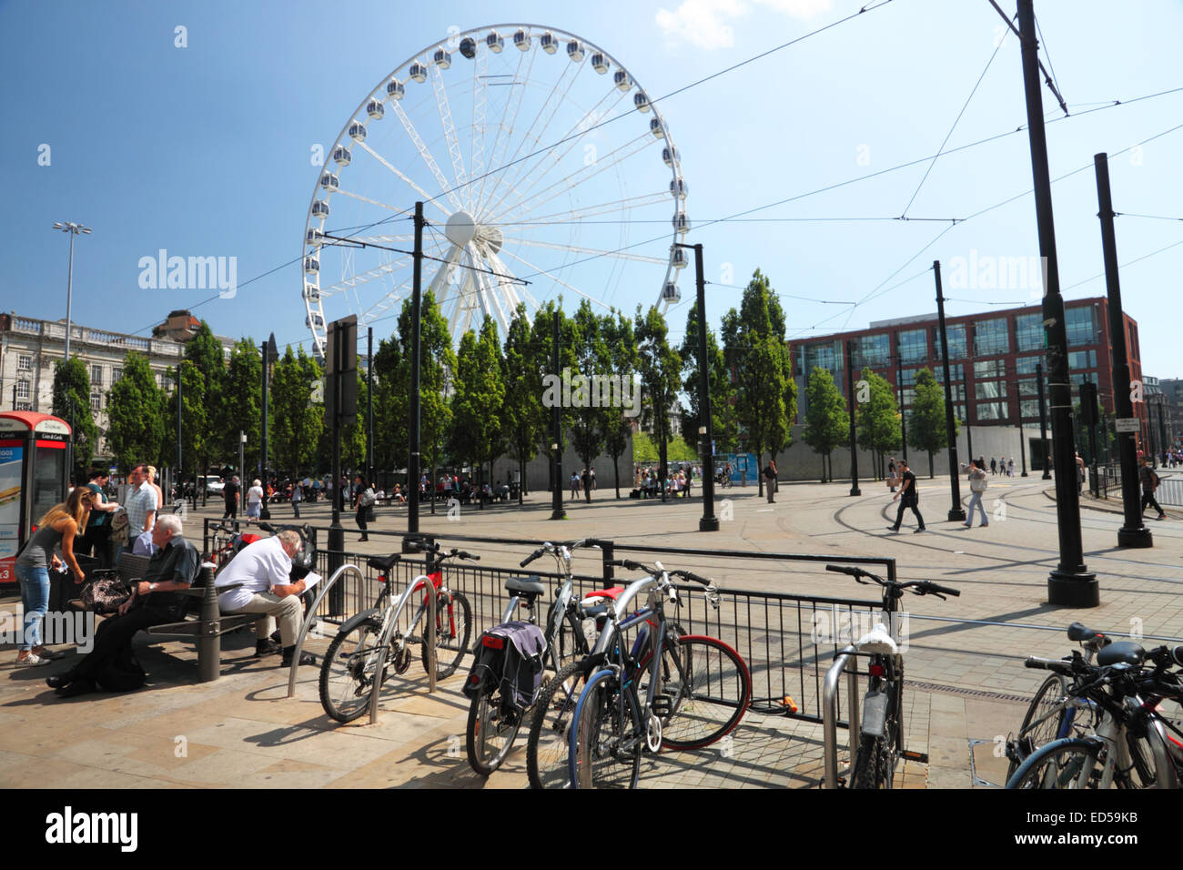 A city centre ferris wheel in a city square with cycles parked in the ...