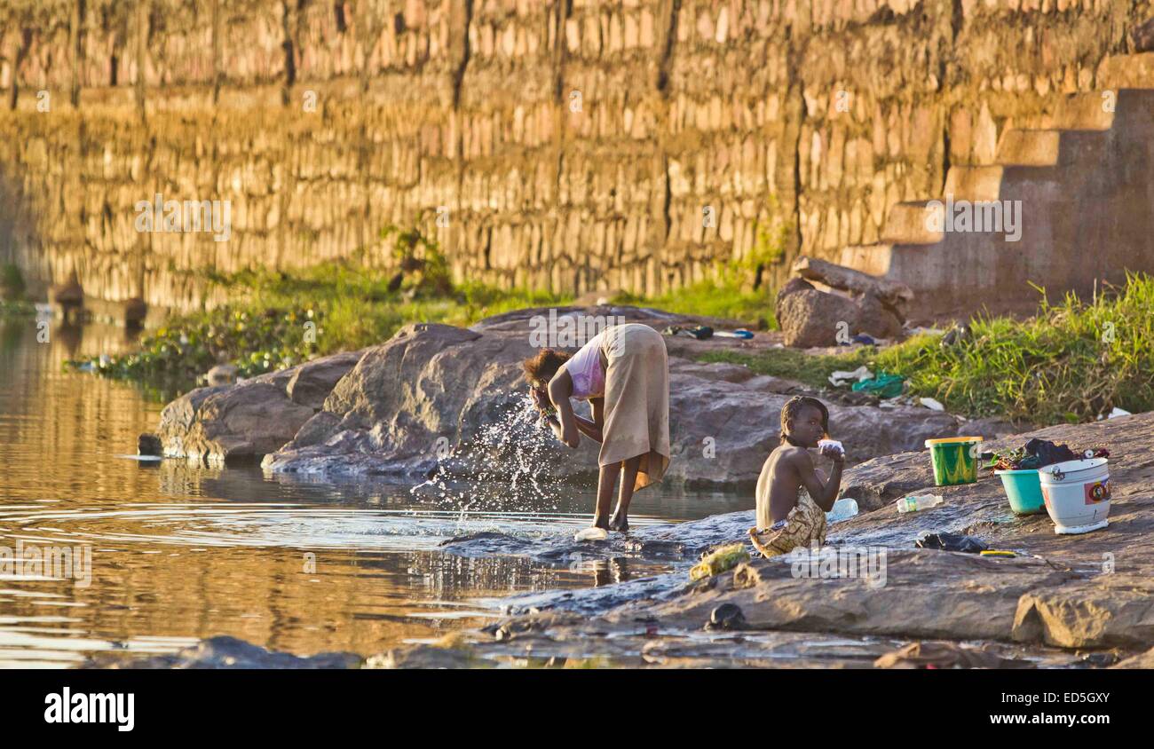 Bamako, Mali. 28th Dec, 2014. Local villagers sit along the river bank ...