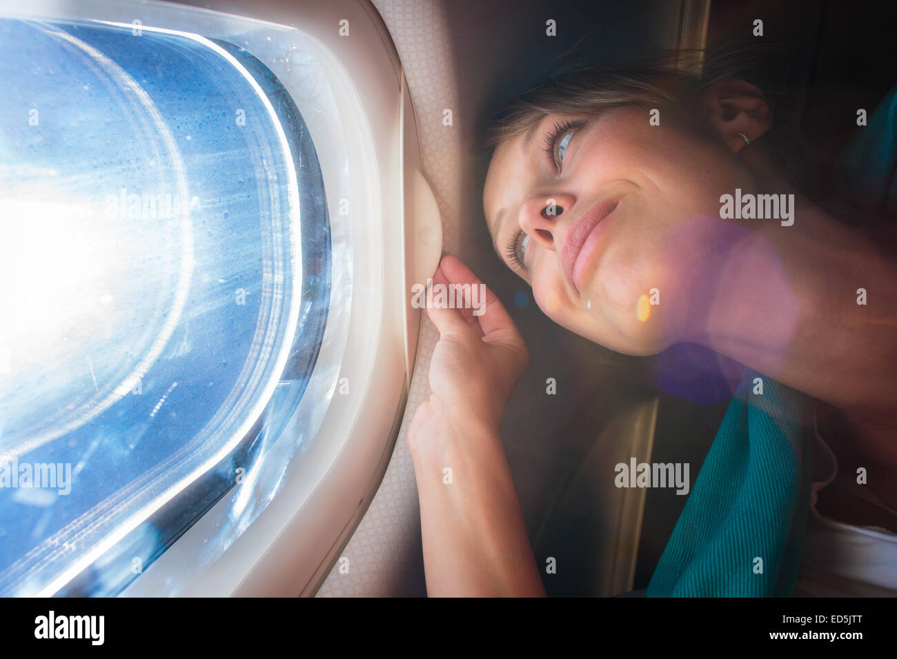 Happy, female airplane passanger enjoying the view from the cabin ...