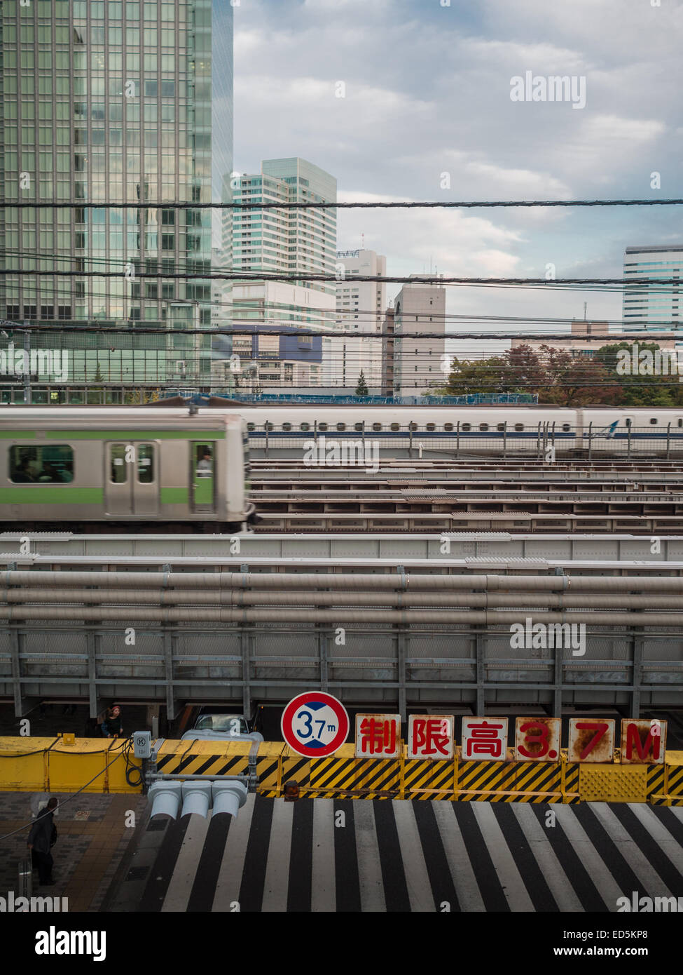 Train lines crossing over a road with skyscrapers in background in ...