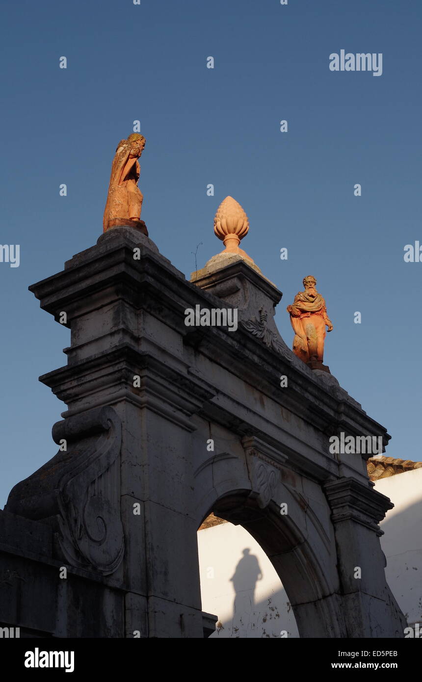 Historic arch with the sunlight hitting the statues on top and casting ...