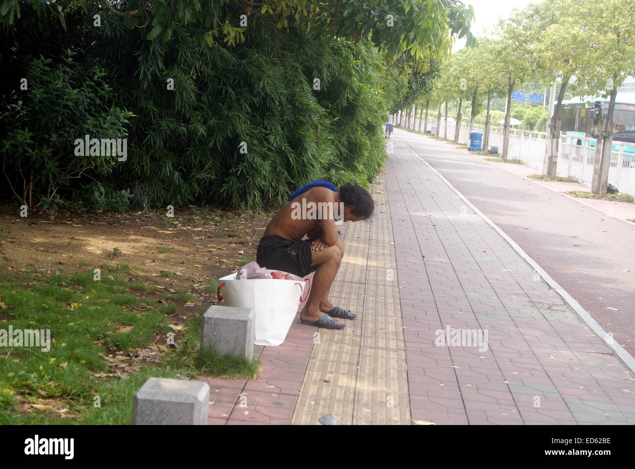 A stray man sitting on the sidewalk. In Shenzhen, china Stock Photo - Alamy