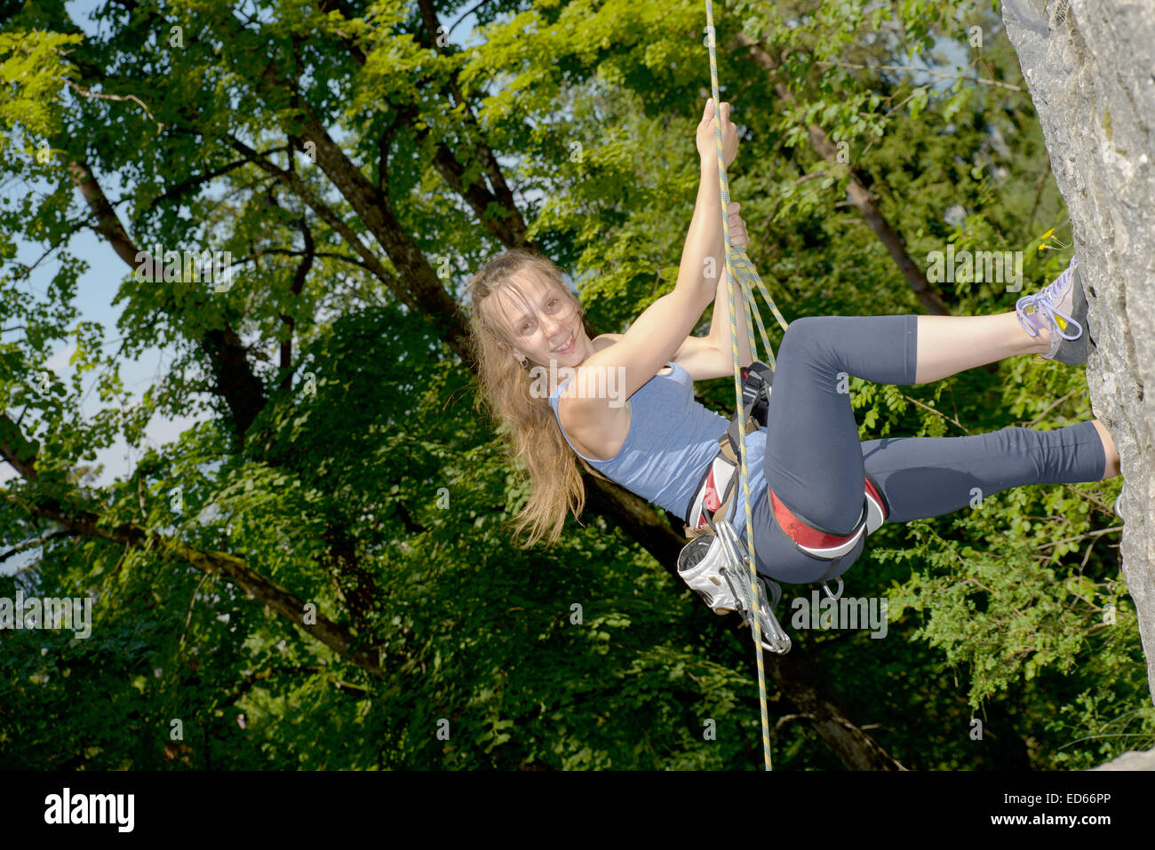 smiling young woman climbing a rock wall Stock Photo - Alamy