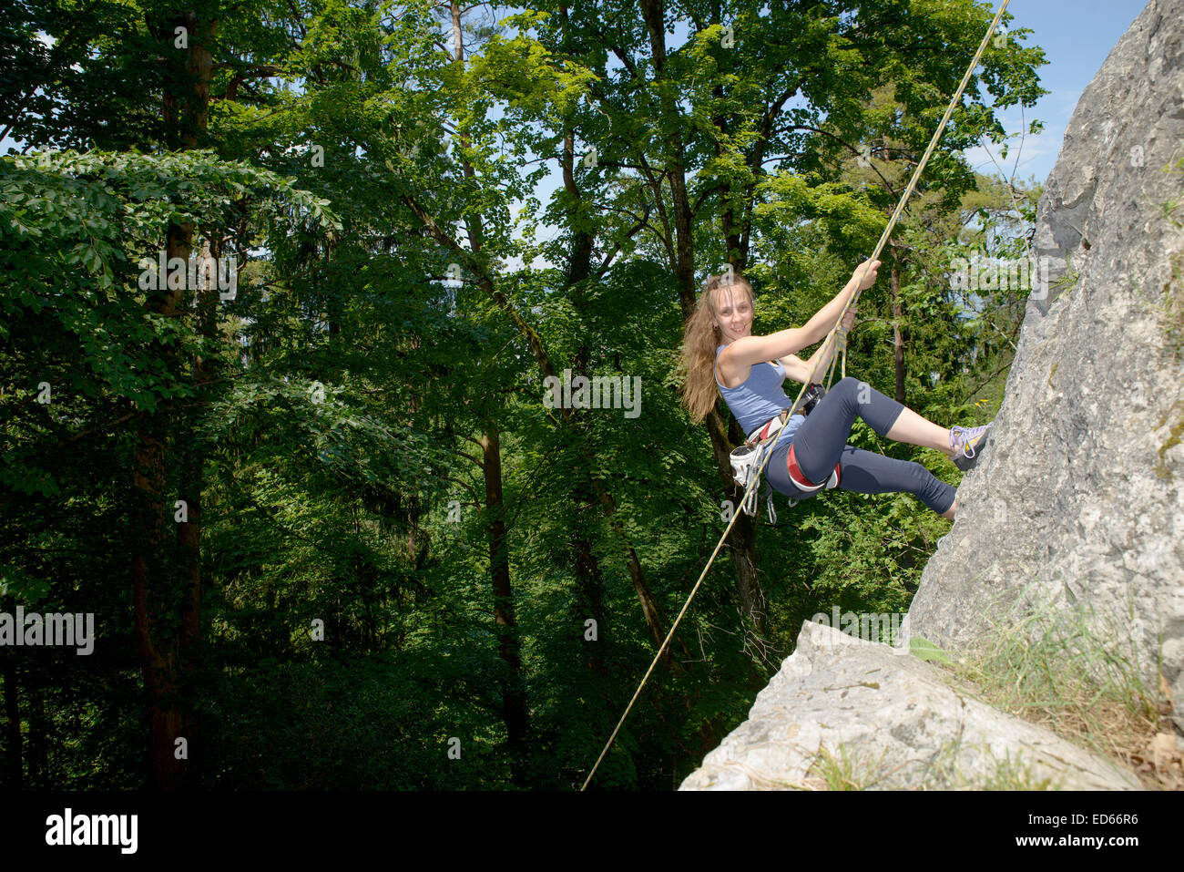 smiling young woman climbing a rock wall Stock Photo - Alamy