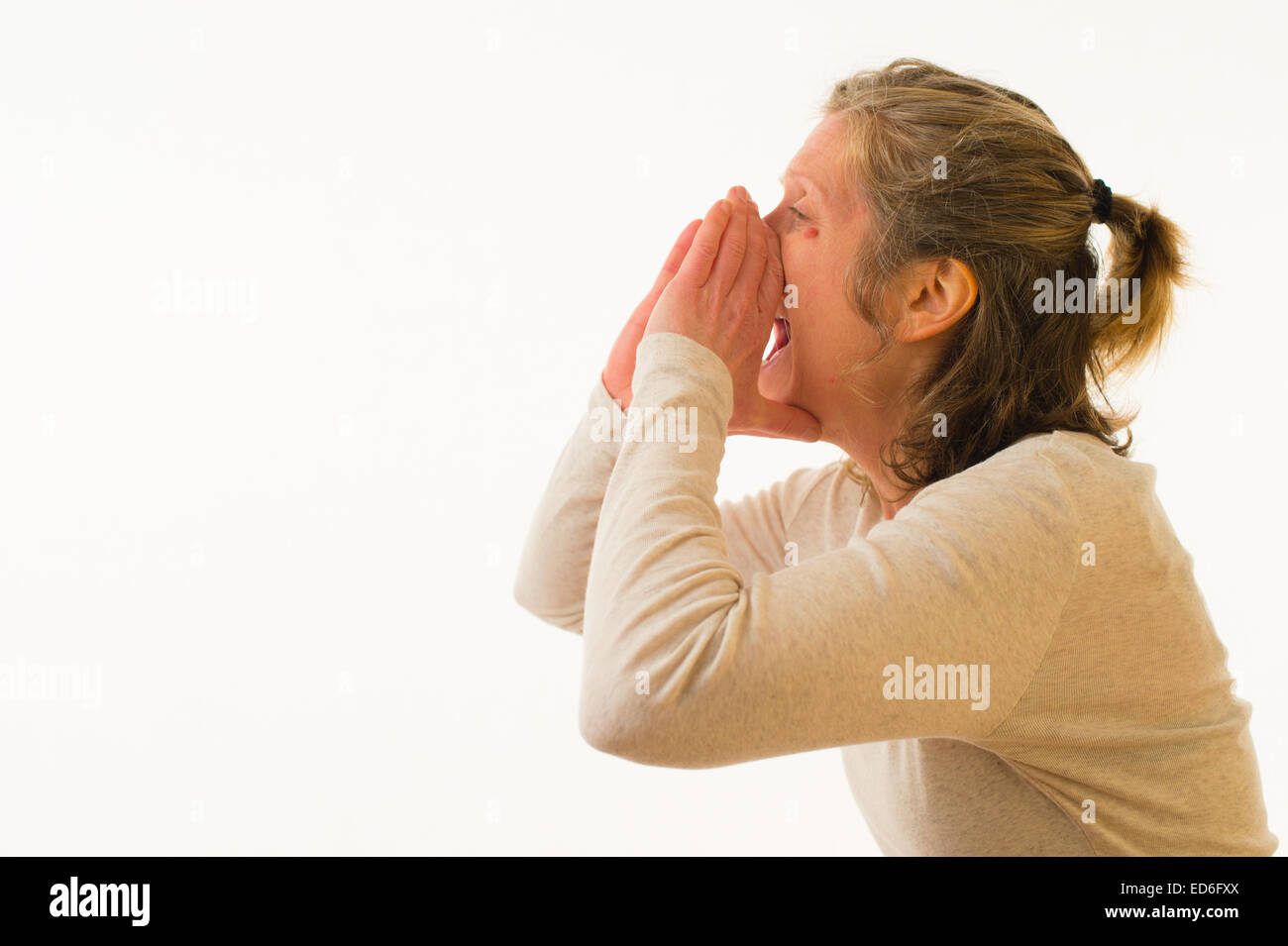 A forty year old caucasian woman shouting yelling through her cupped ...