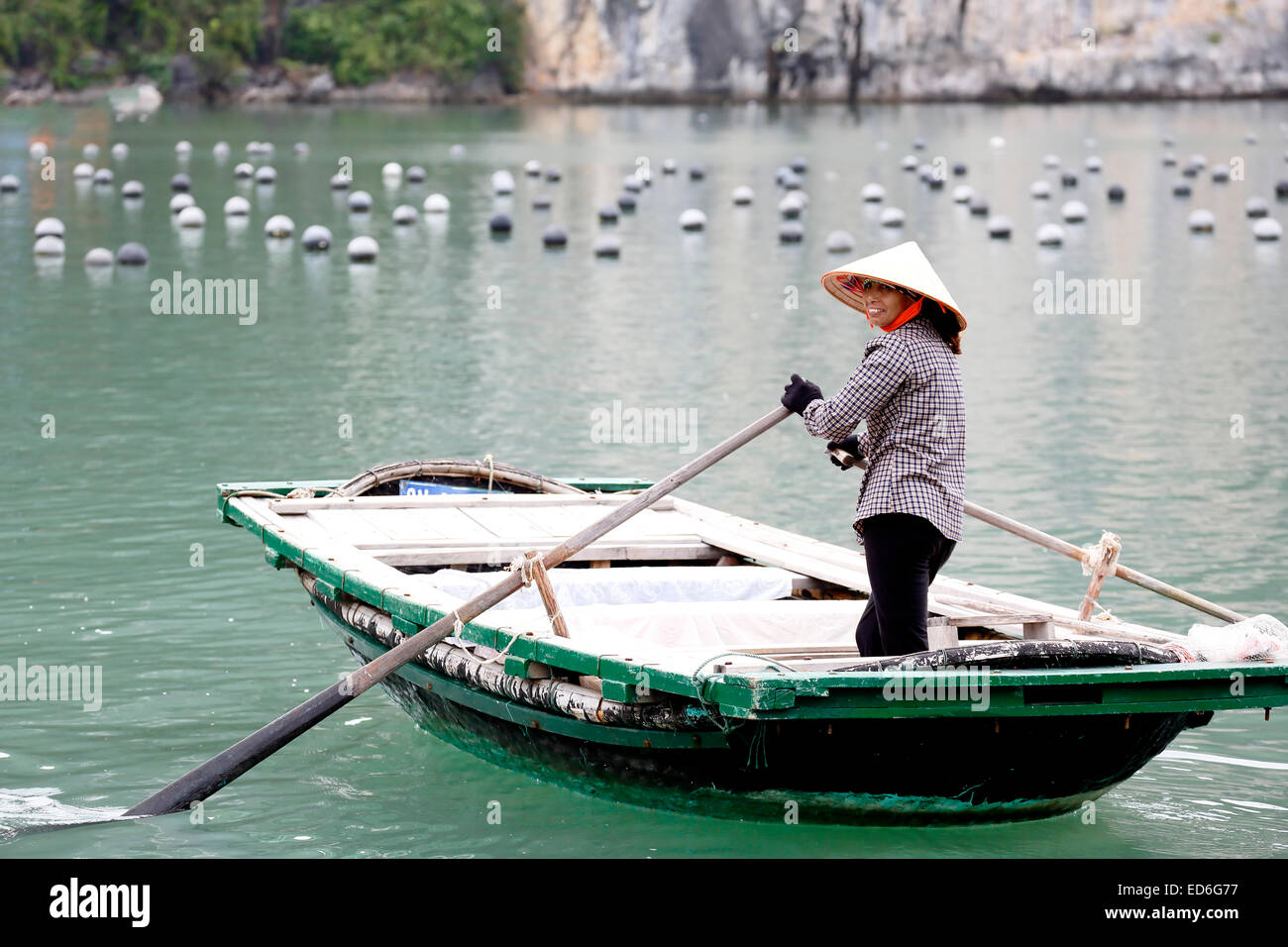 Woman rowing wooden rowboat and pearl farm buoys, Vung Vieng fishing ...