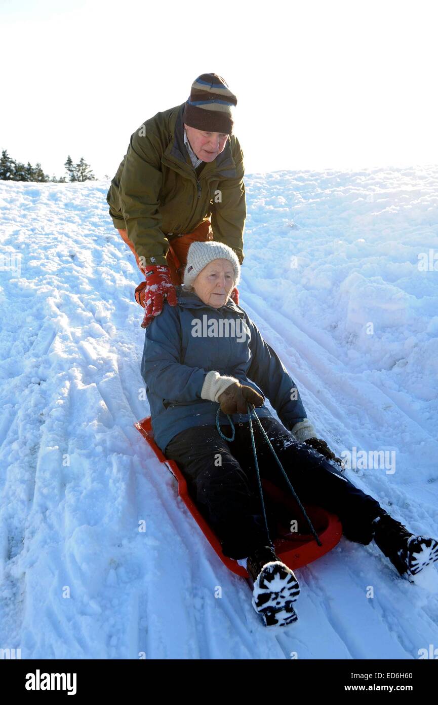 Lifestyle shot of active senior couple on sledge having fun in the snow ...