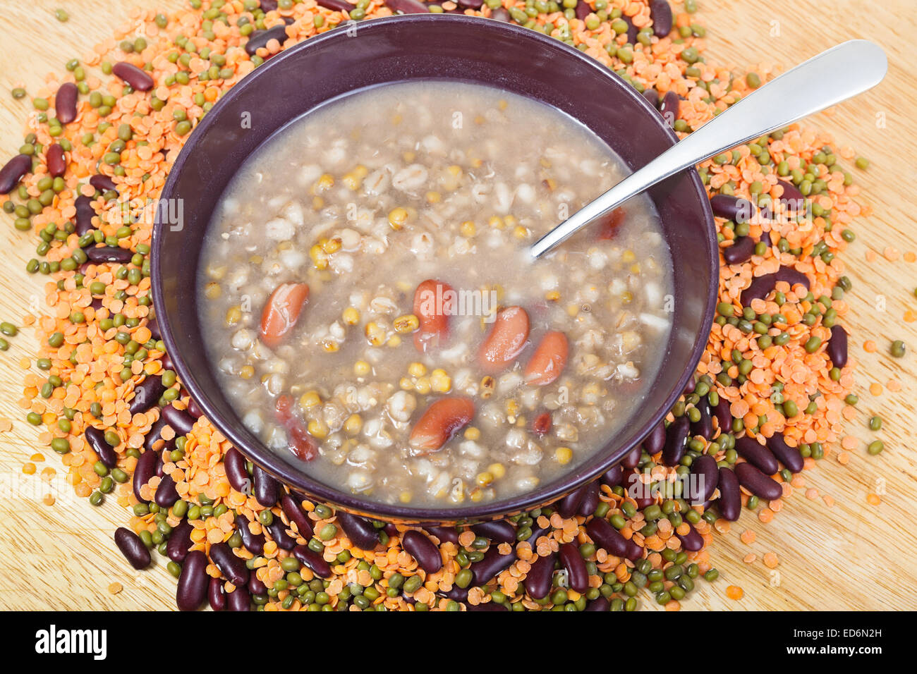 top view of mess of pottage in bowl with tablespoon on wooden plate ...