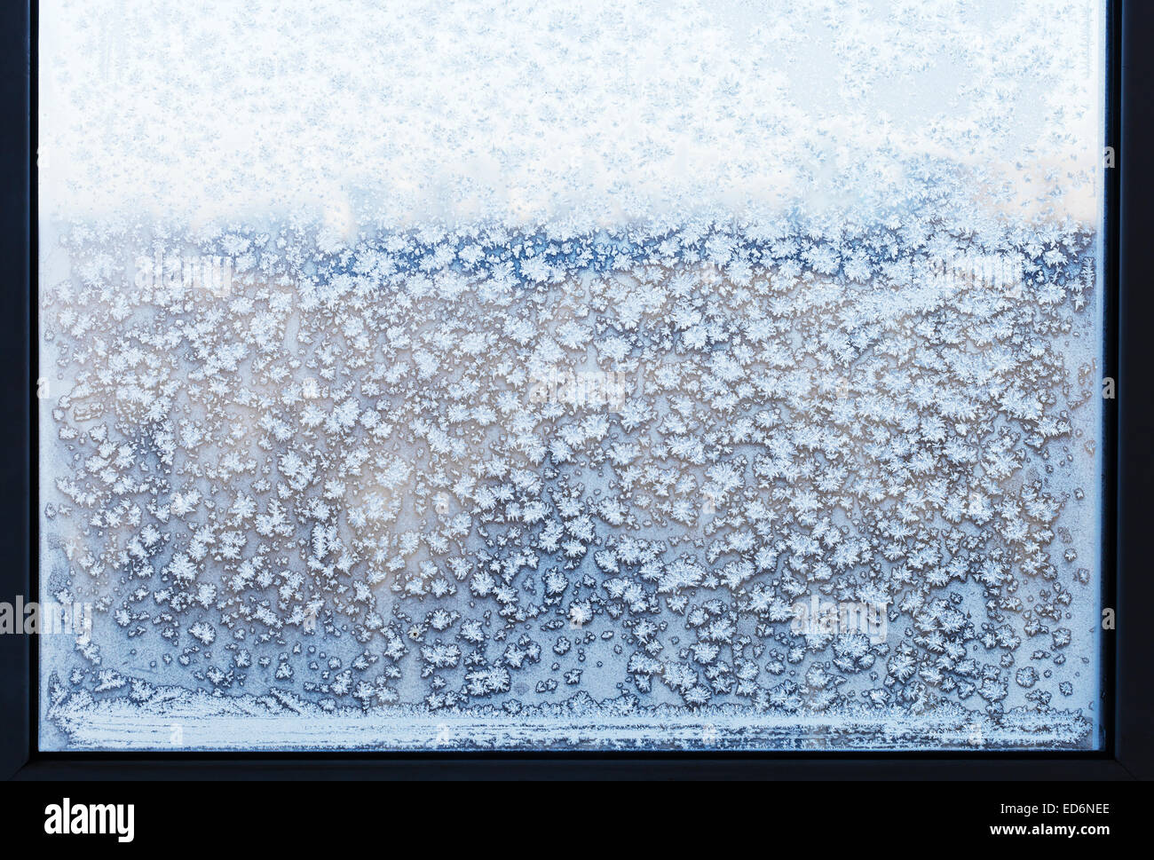 snowflakes and frost pattern on frozen windowpane in cold winter day ...