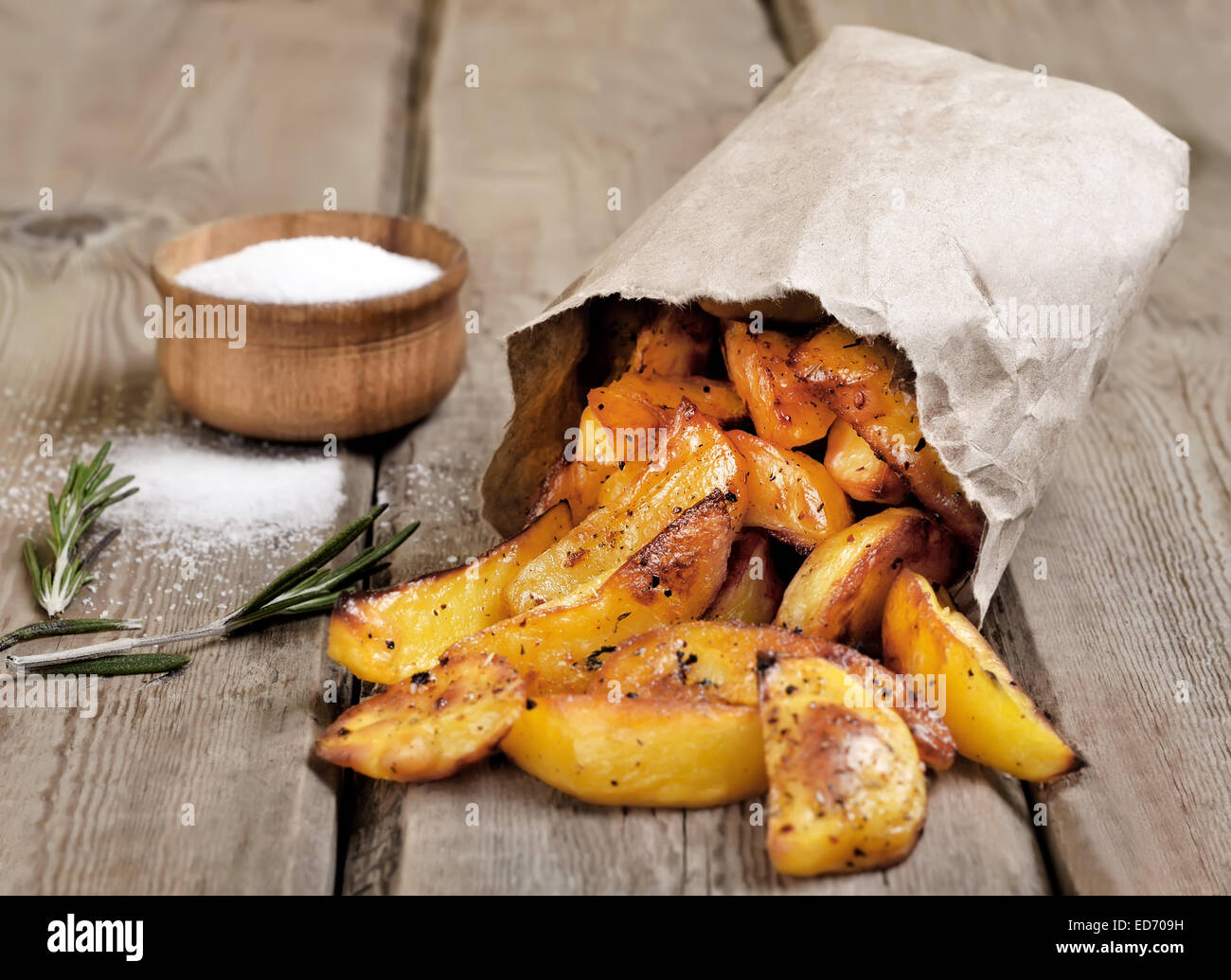 Baked potato wedges in paper bag on rustic table Stock Photo - Alamy