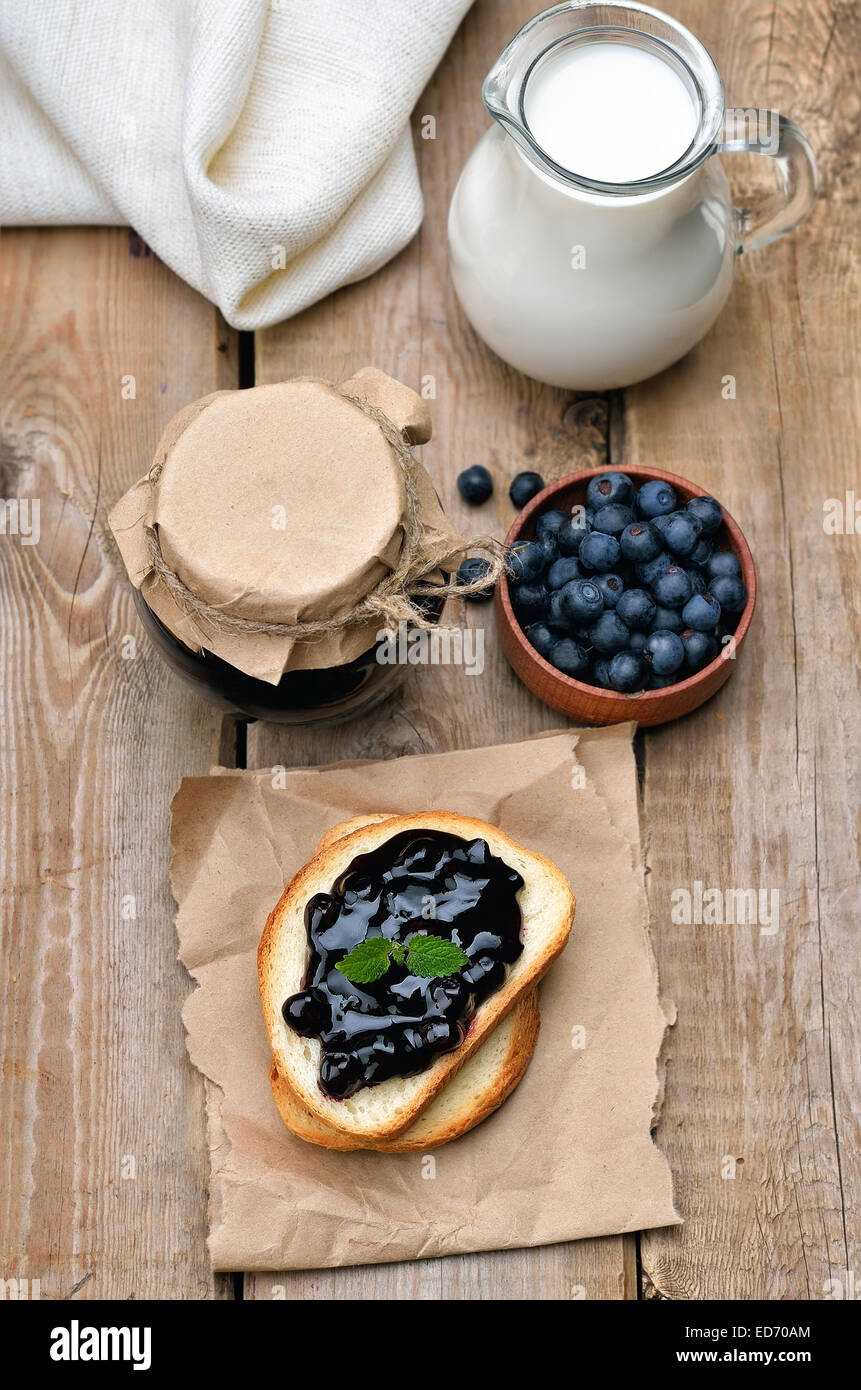 Bread with blueberry jam, jam in glass jar, fresh berries and jug of ...