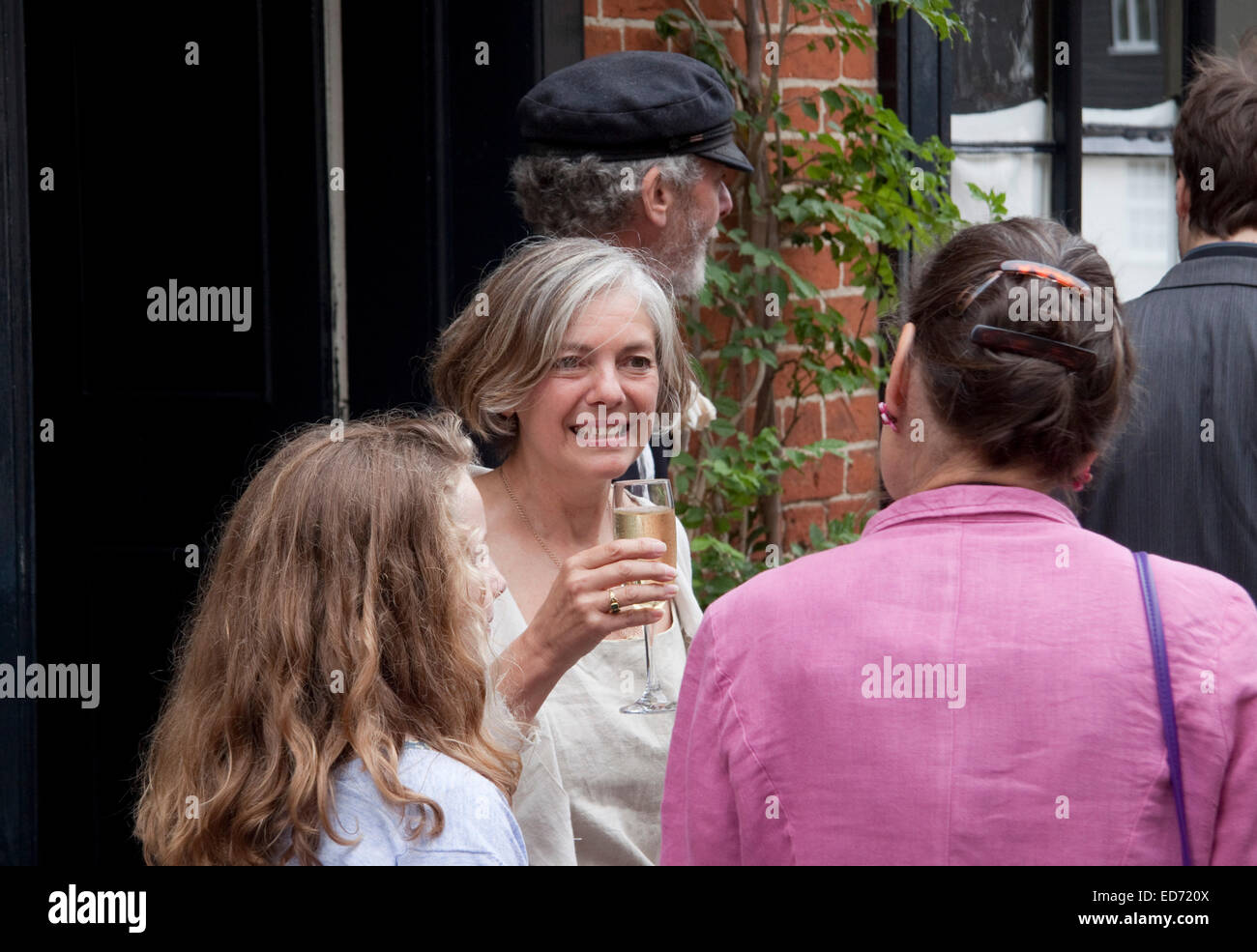 A woman holds a glass of wine and listens to a friend Stock Photo - Alamy