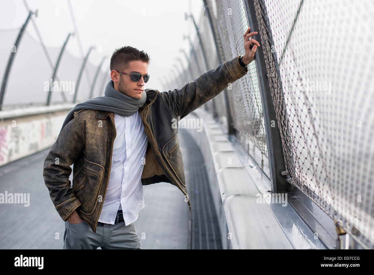 Handsome trendy man standing on a bridge, looking down Stock Photo - Alamy