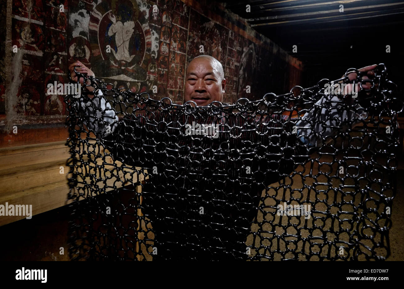 A Buddhist devotee spreading a heavy chain-mail coat which was made ...