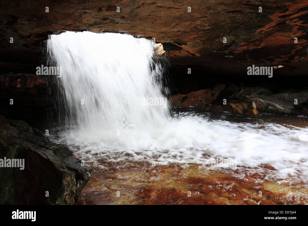 River flowing through a hole in a rock overhang in the Gifberg mountain ...