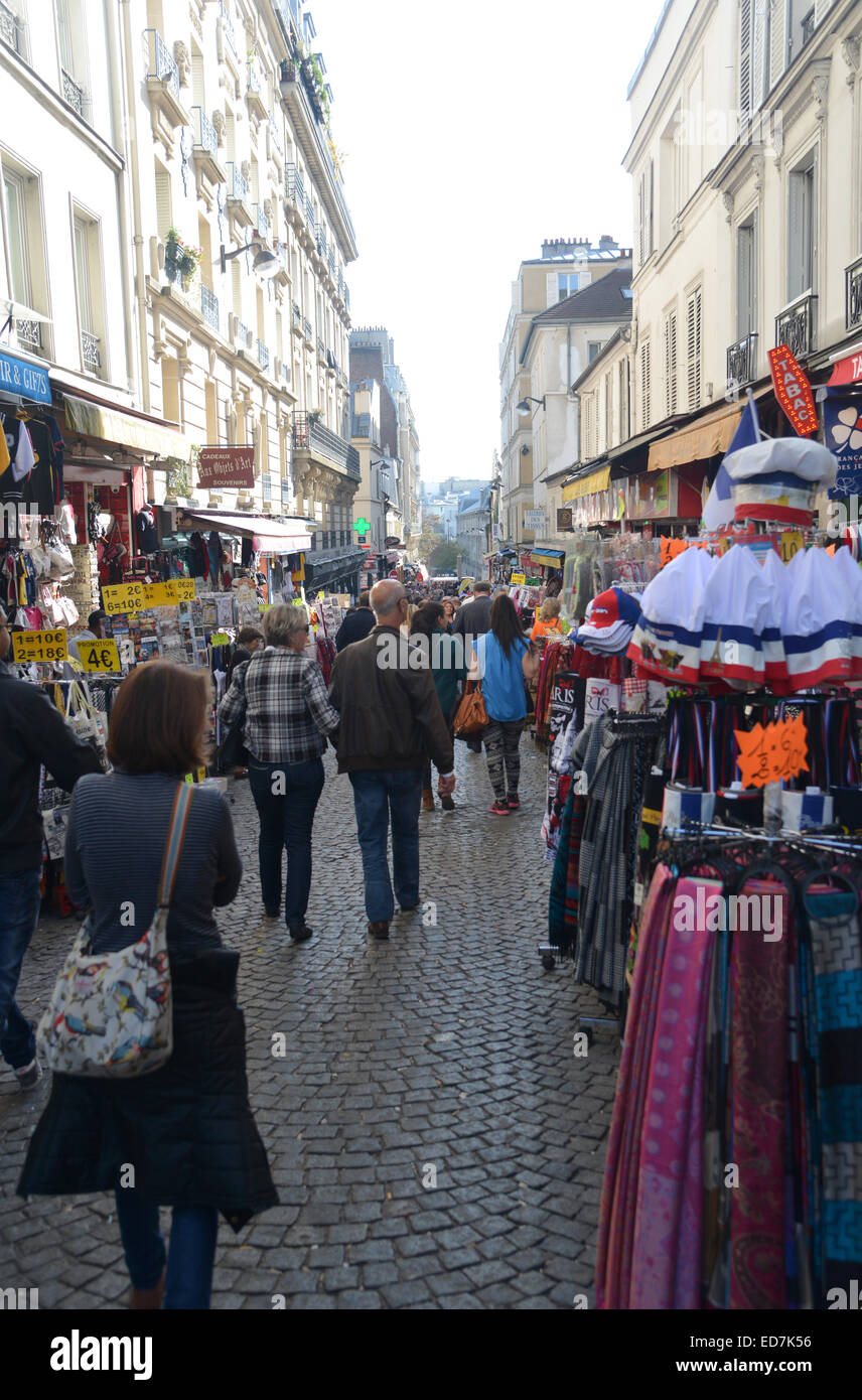 Tourists walk through a narrow and busy Paris street with shop displays ...