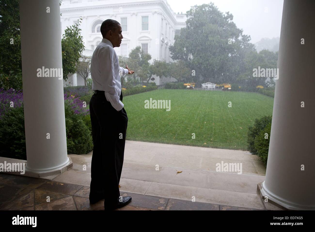 US President Barack Obama reaches out to touch the rain from the ...