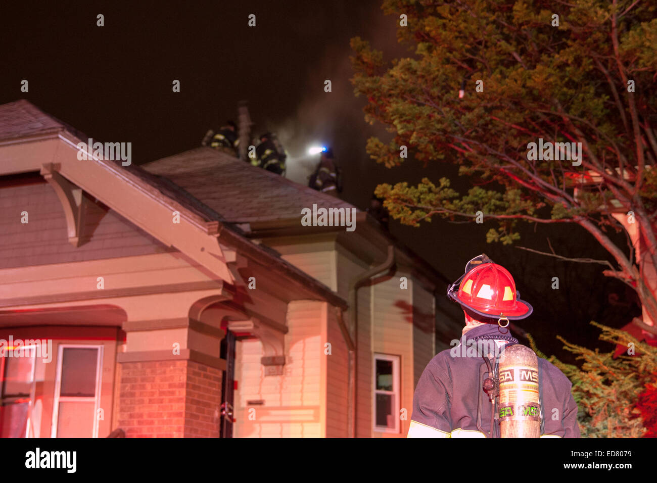 Milwaukee Firefighters Leutenant watching crews on the roof of a house ...