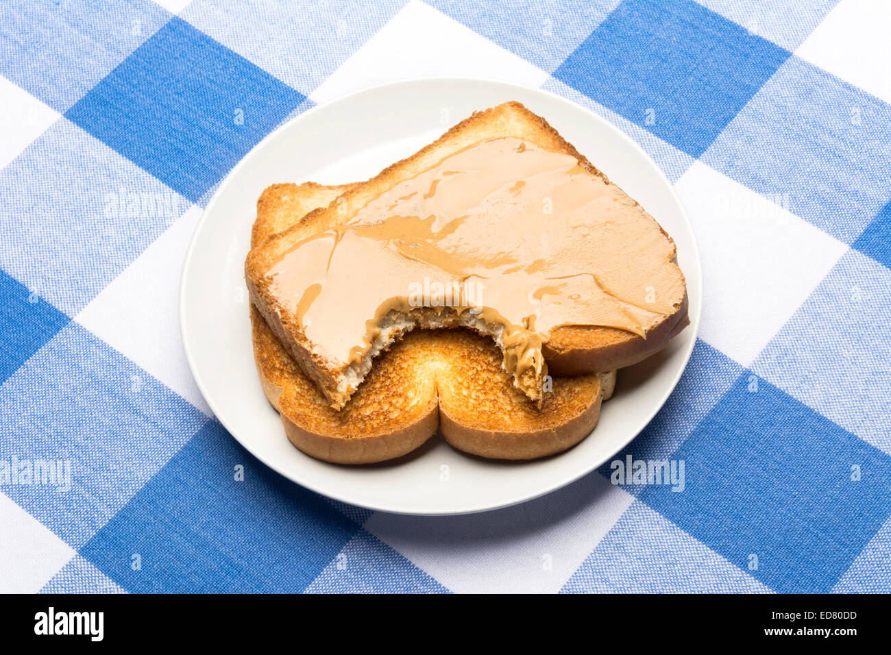 Fresh, hot toast spread with peanut butter sits with a bite taken out ...