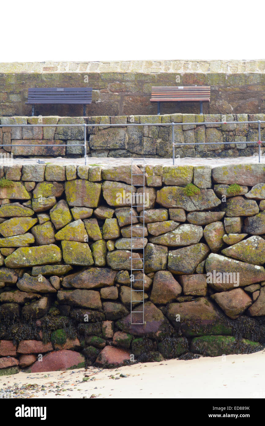 Mousehole harbour wall rocks colour stained by sea and plant life ...