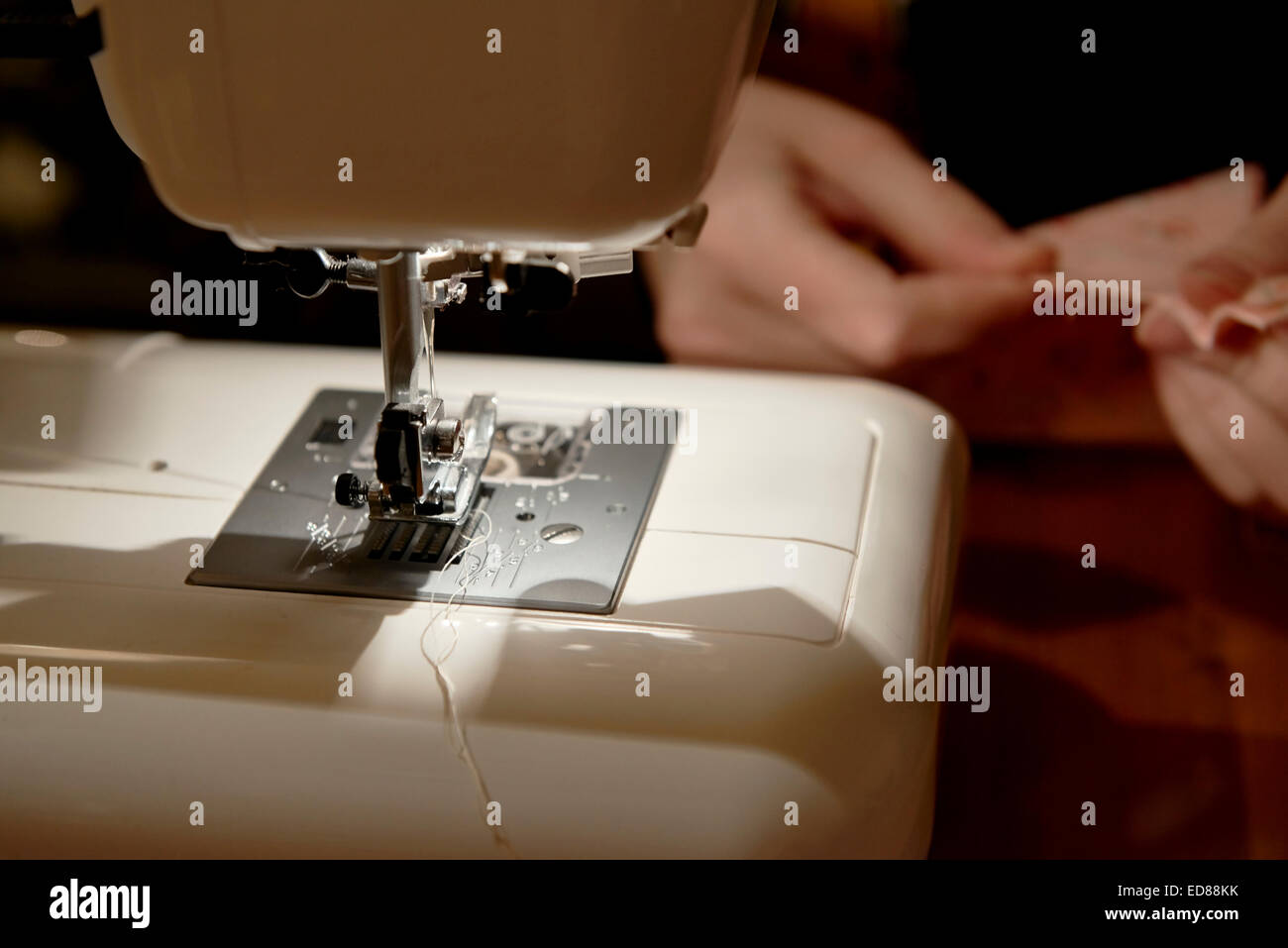 Detail of automatic sewing machine with hands working on piece of ...
