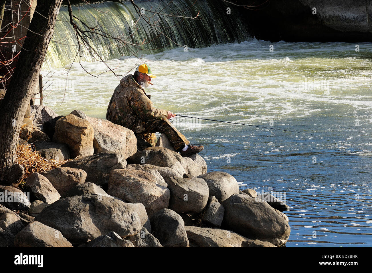 Lone fisherman fishing from shoreline near river dam Stock Photo - Alamy