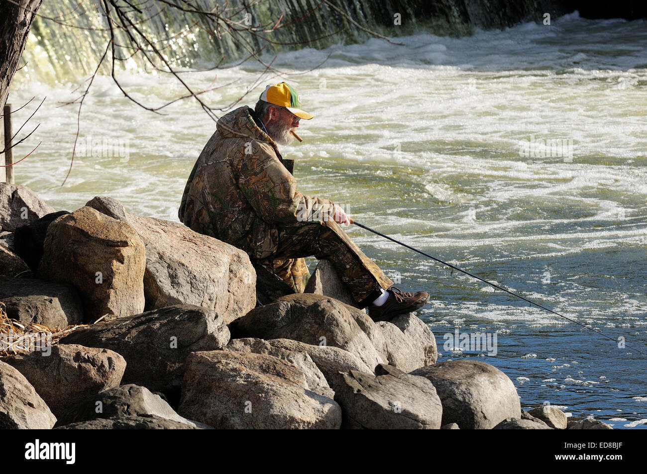 Lone fisherman fishing from shoreline near river dam Stock Photo - Alamy