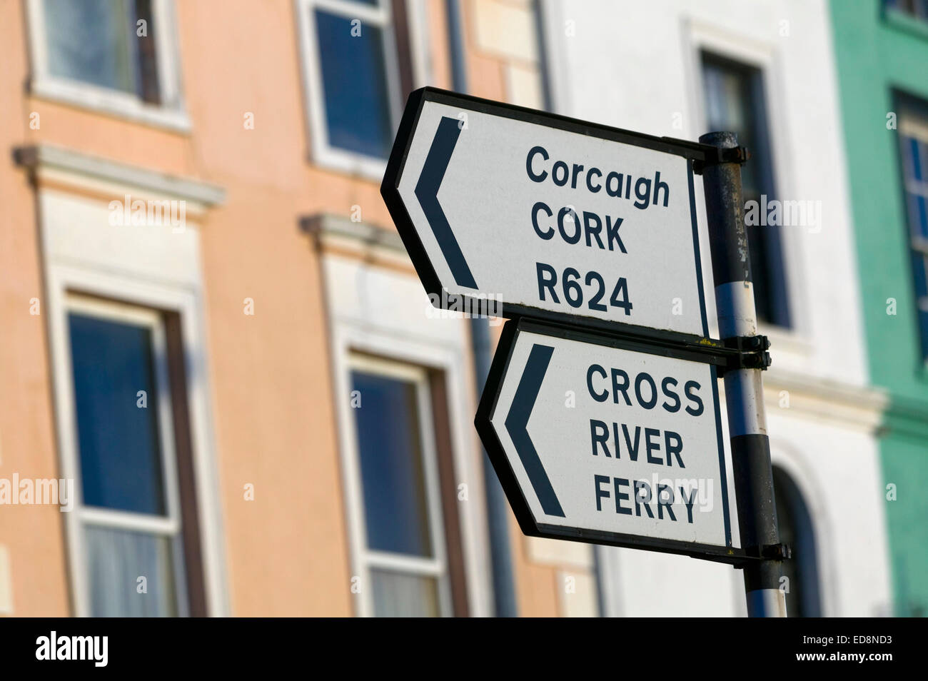 Signposts to Cork, Corcaigh, in front of houses in the Irish colours ...