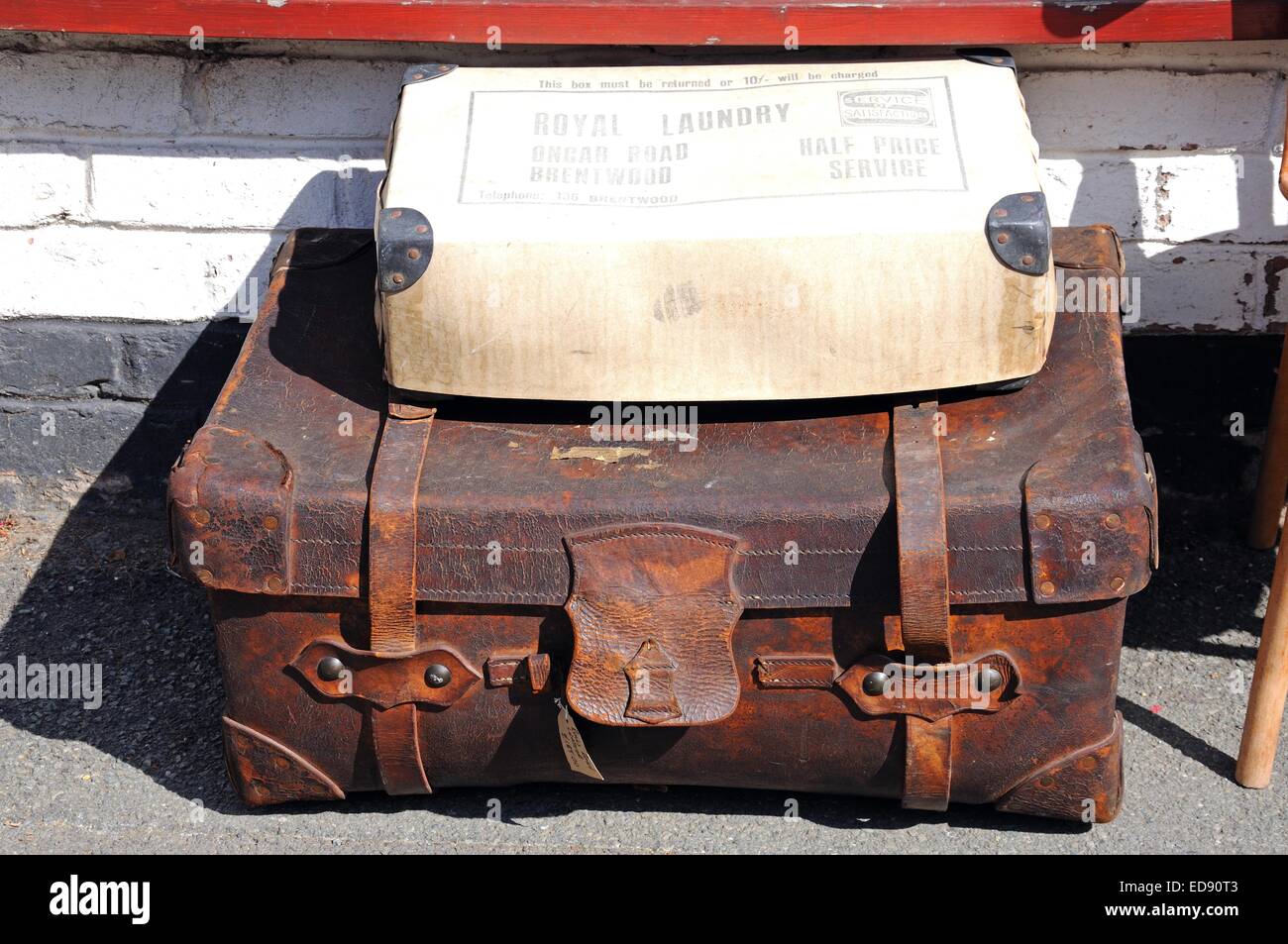 Old rustic suitcase with a Laundry service box on top on the pavement ...