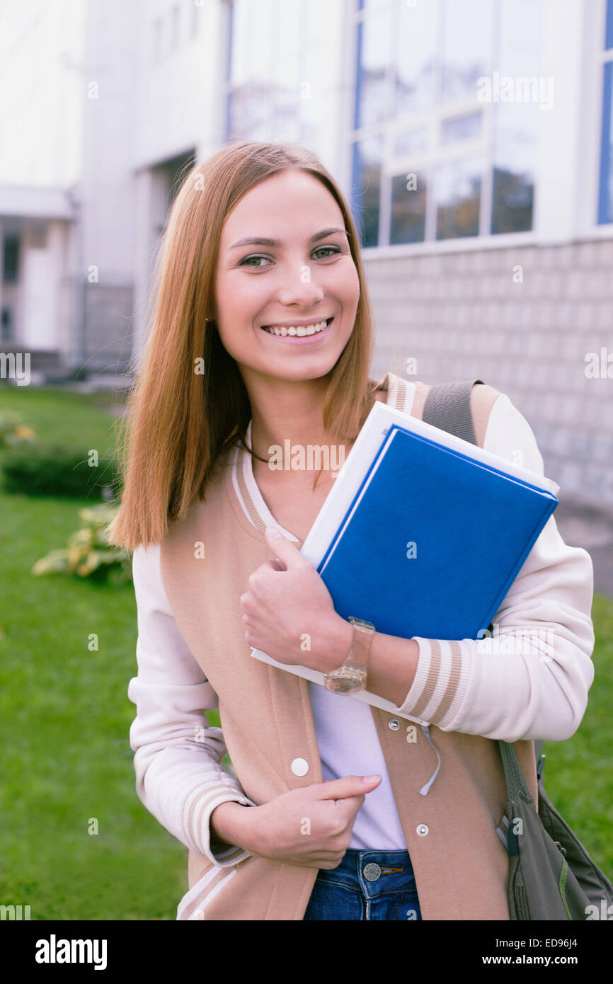 Student standing with book in her hands and laughing Stock Photo - Alamy