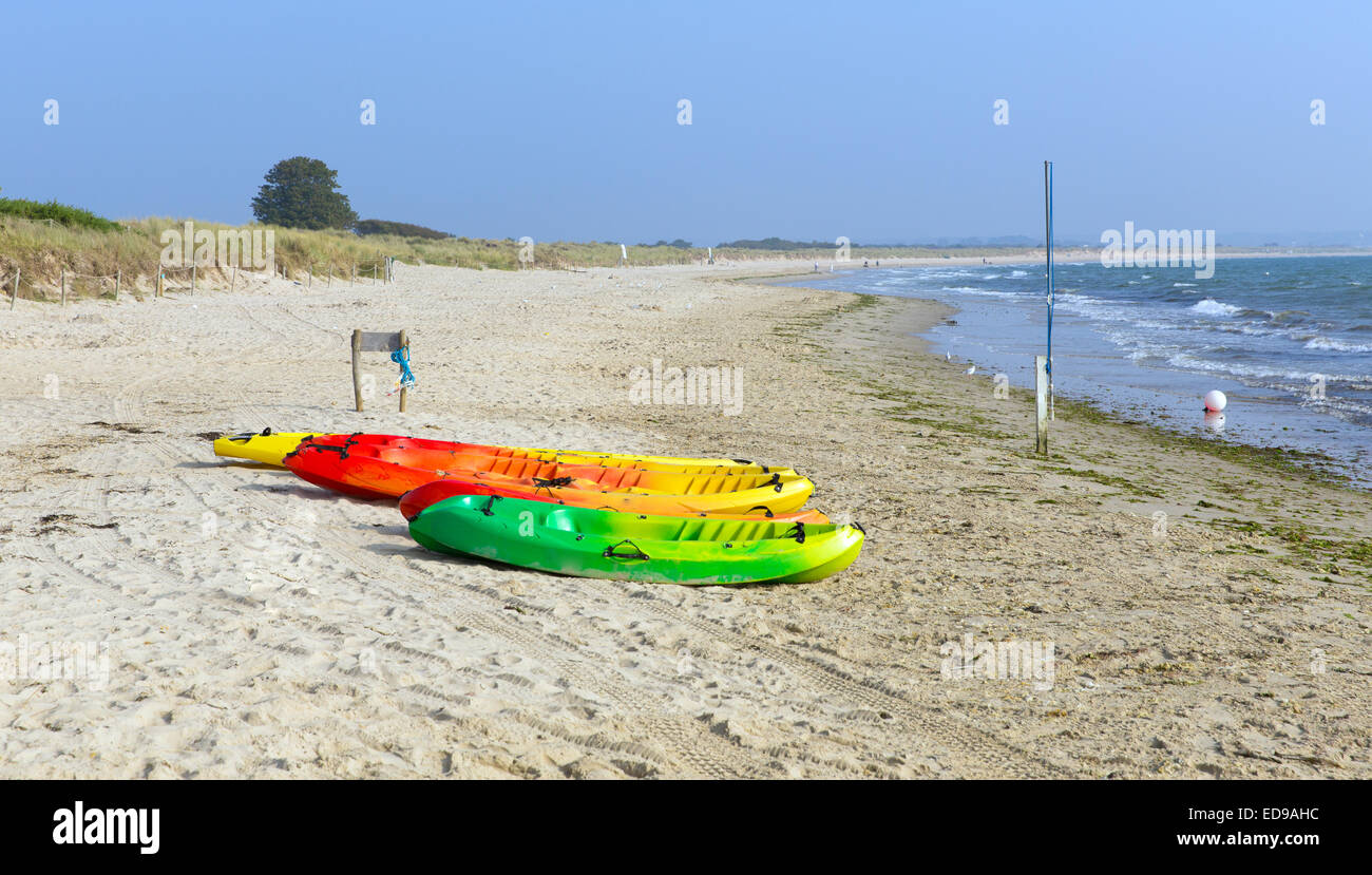 Brightly coloured canoes Studland knoll beach Dorset England UK located ...