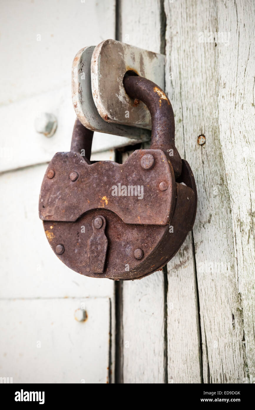Big old rusted padlock hanging on white rural door Stock Photo - Alamy
