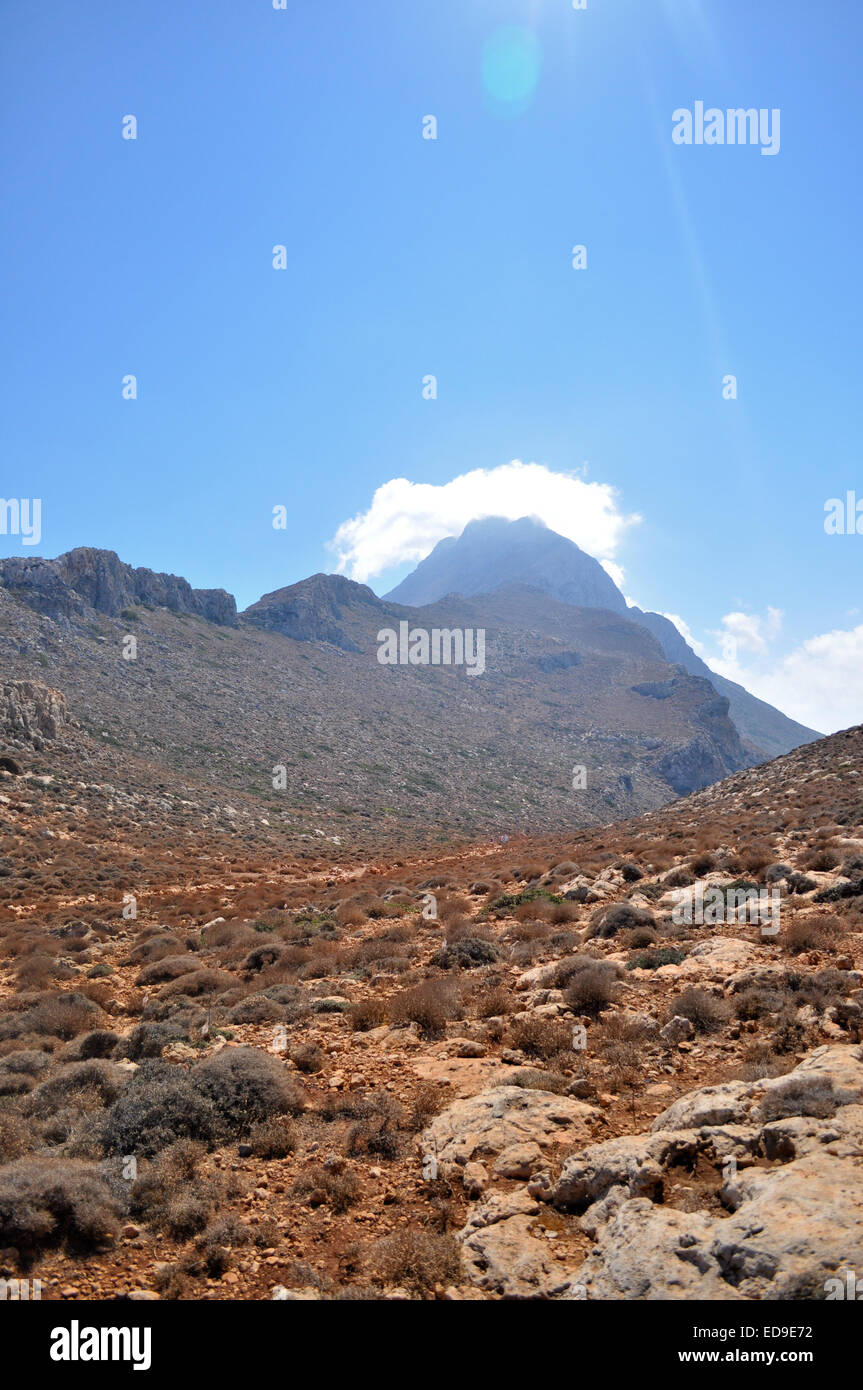 Red dusty road in the mountains on the Greek island. Mediterranean sea ...