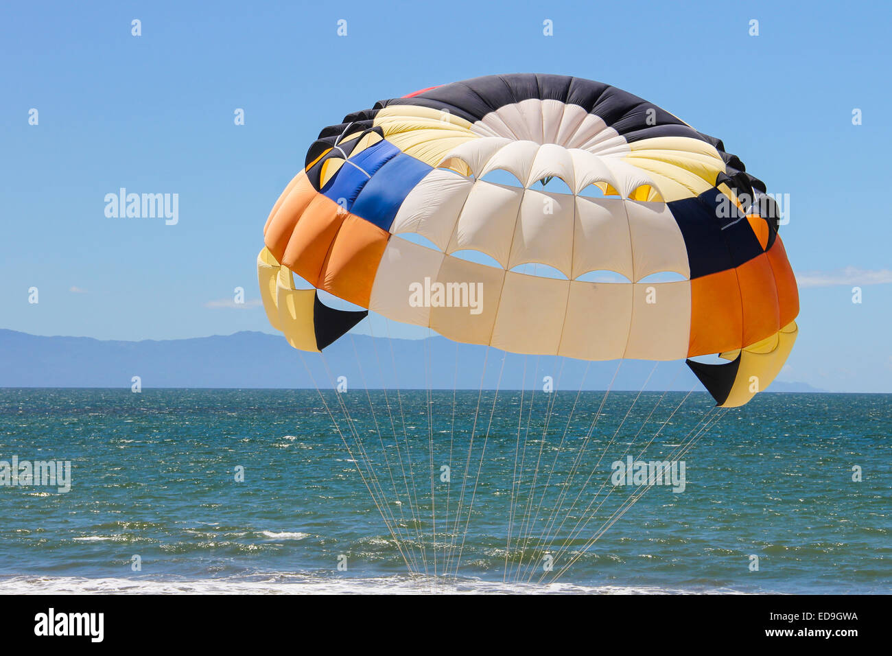 A bright colored parasail over the blue waters of the Pacific coast of ...