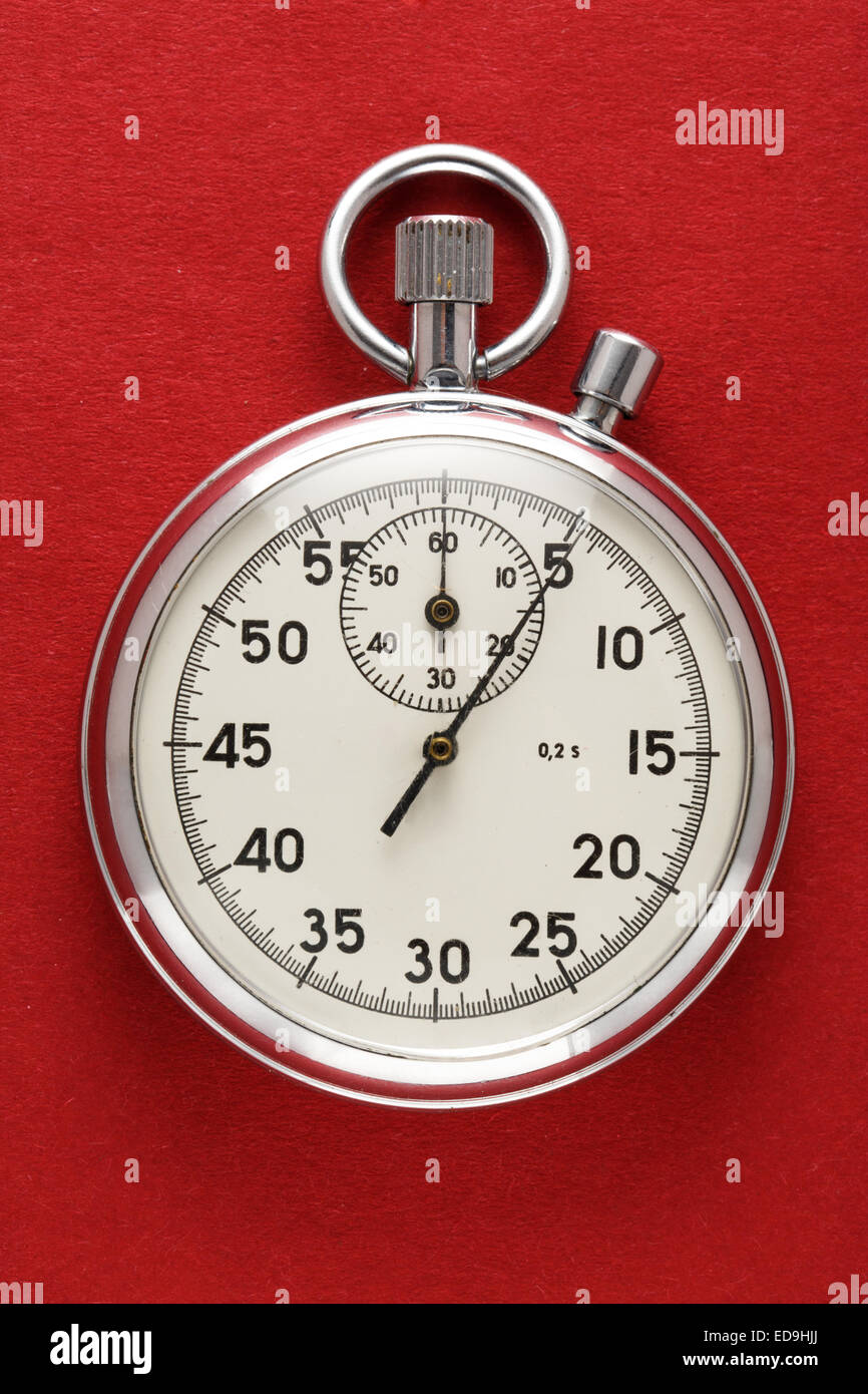 Single stopwatch closeup on red paper background Stock Photo - Alamy