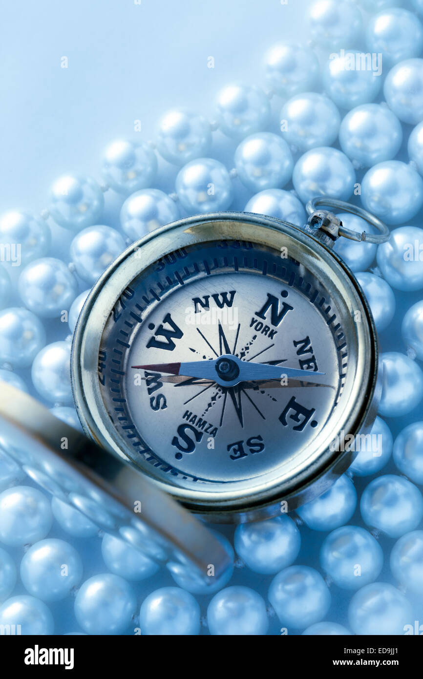 Golden compass on pearl necklace as background Stock Photo - Alamy
