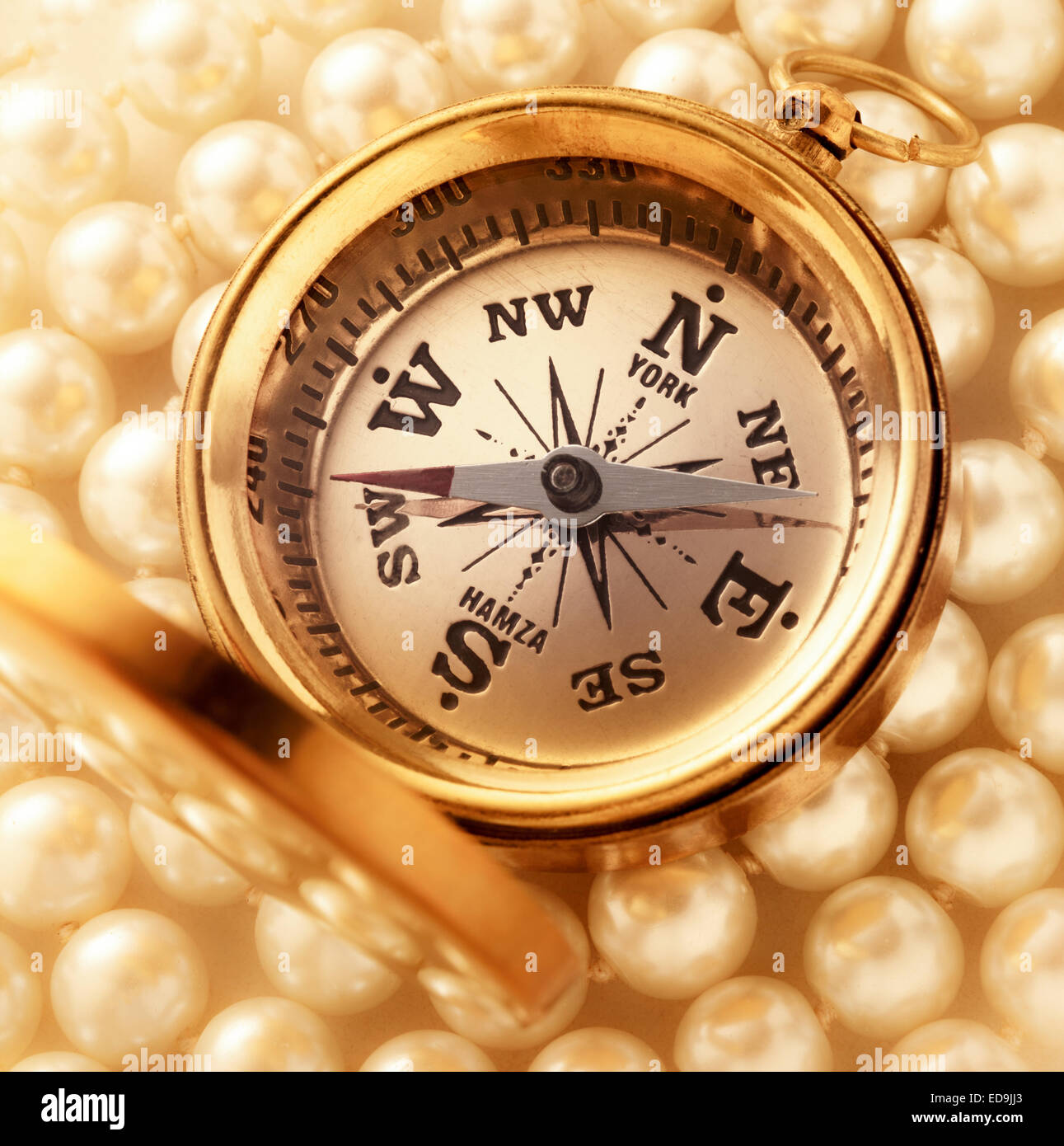 Golden compass on pearl necklace as background Stock Photo - Alamy