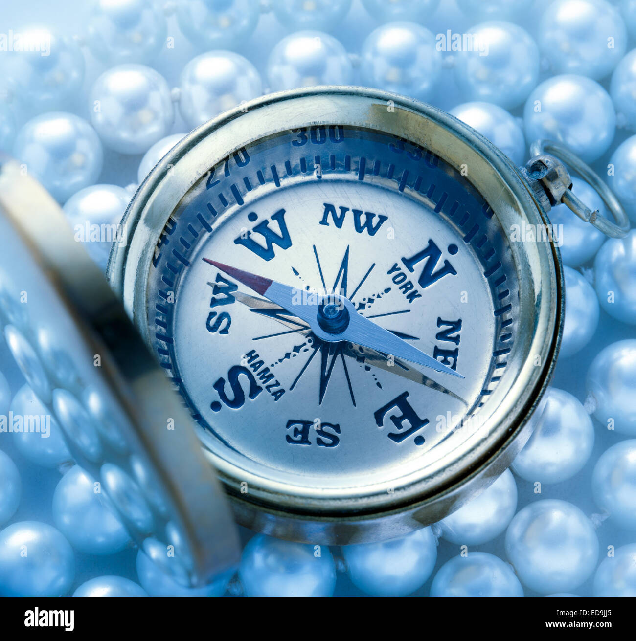 Golden compass on pearl necklace as background Stock Photo - Alamy