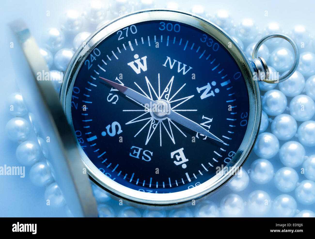 Golden compass on pearl necklace as background Stock Photo - Alamy