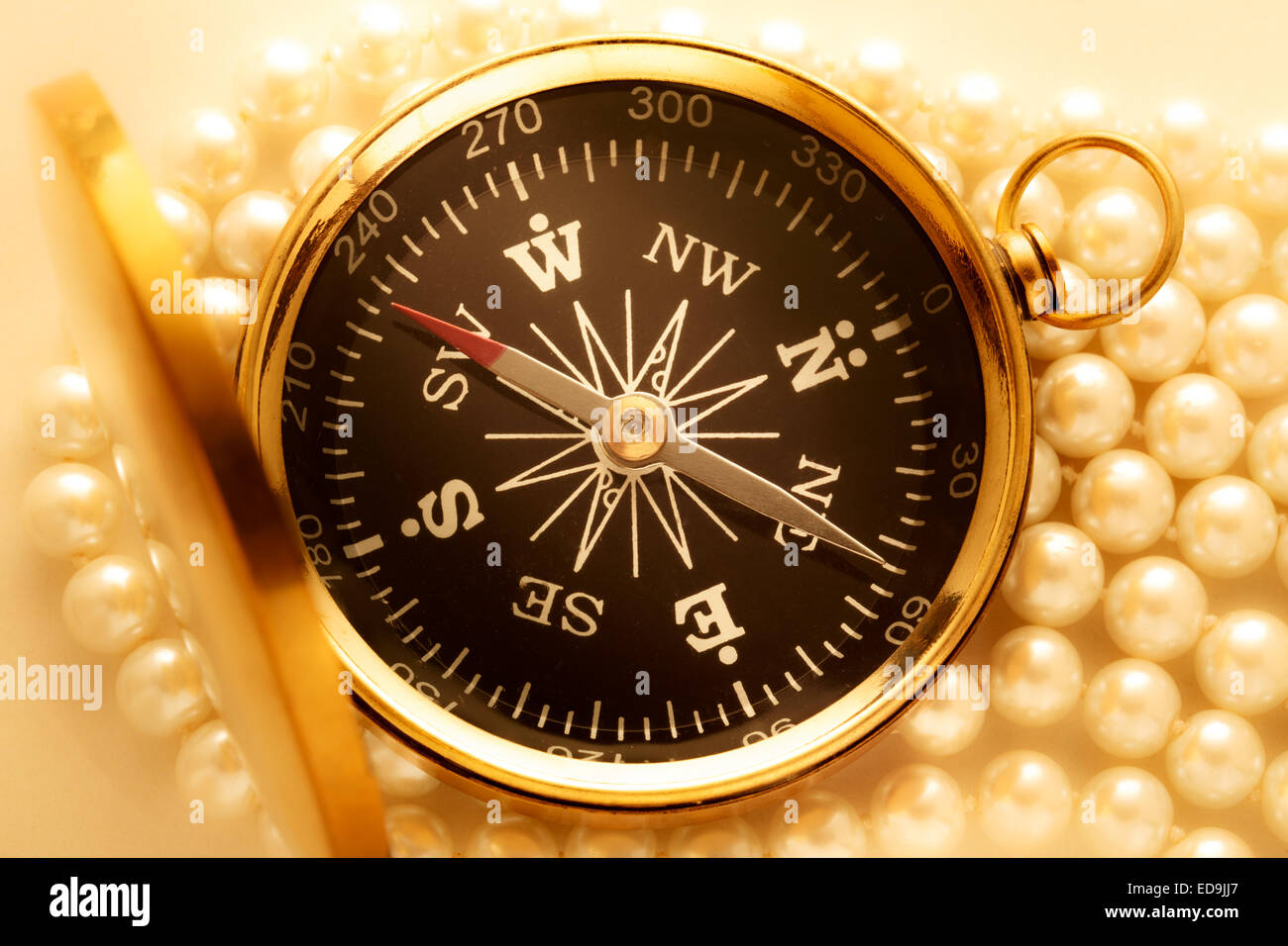 Golden compass on pearl necklace as background Stock Photo - Alamy