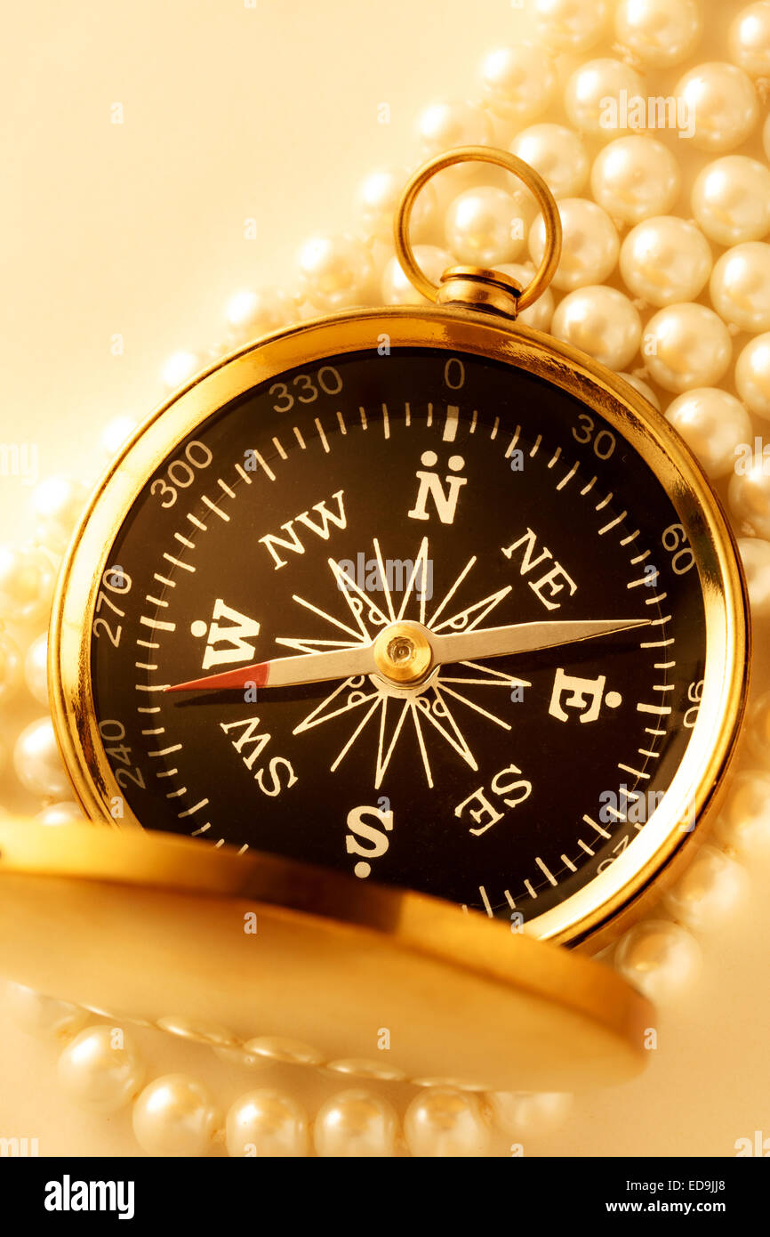 Golden compass on pearl necklace as background Stock Photo - Alamy