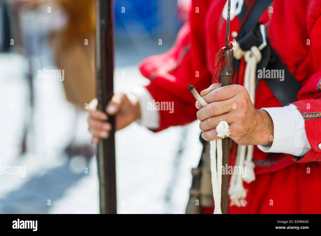Hands of a musketeer holding a musket and slow match or match cord with ...