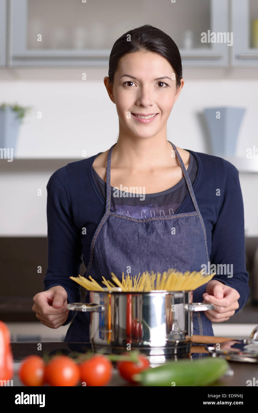 Young housewife preparing a healthy Italian pasta standing at the stove ...