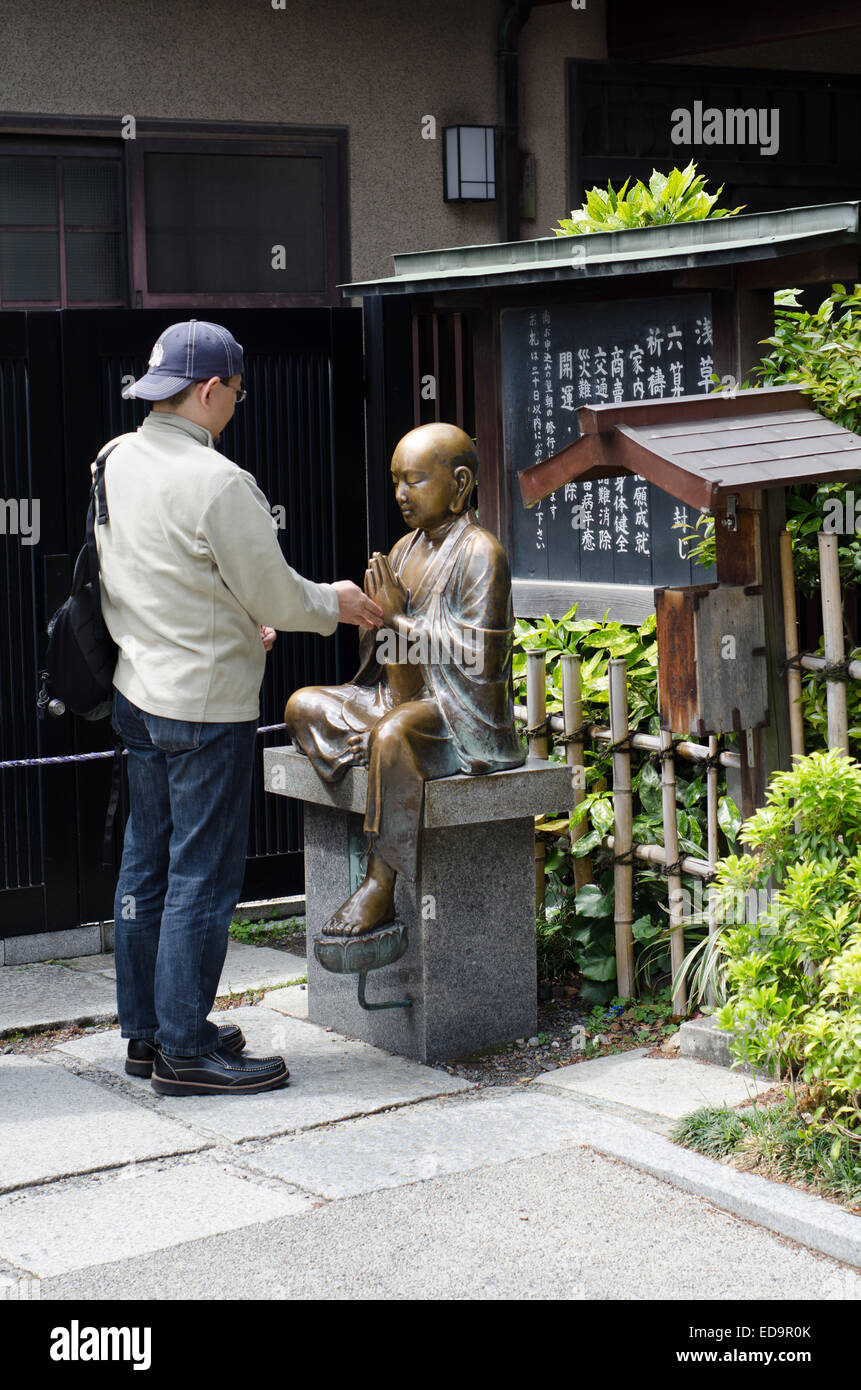 man praying in front of a buddha statue Stock Photo - Alamy