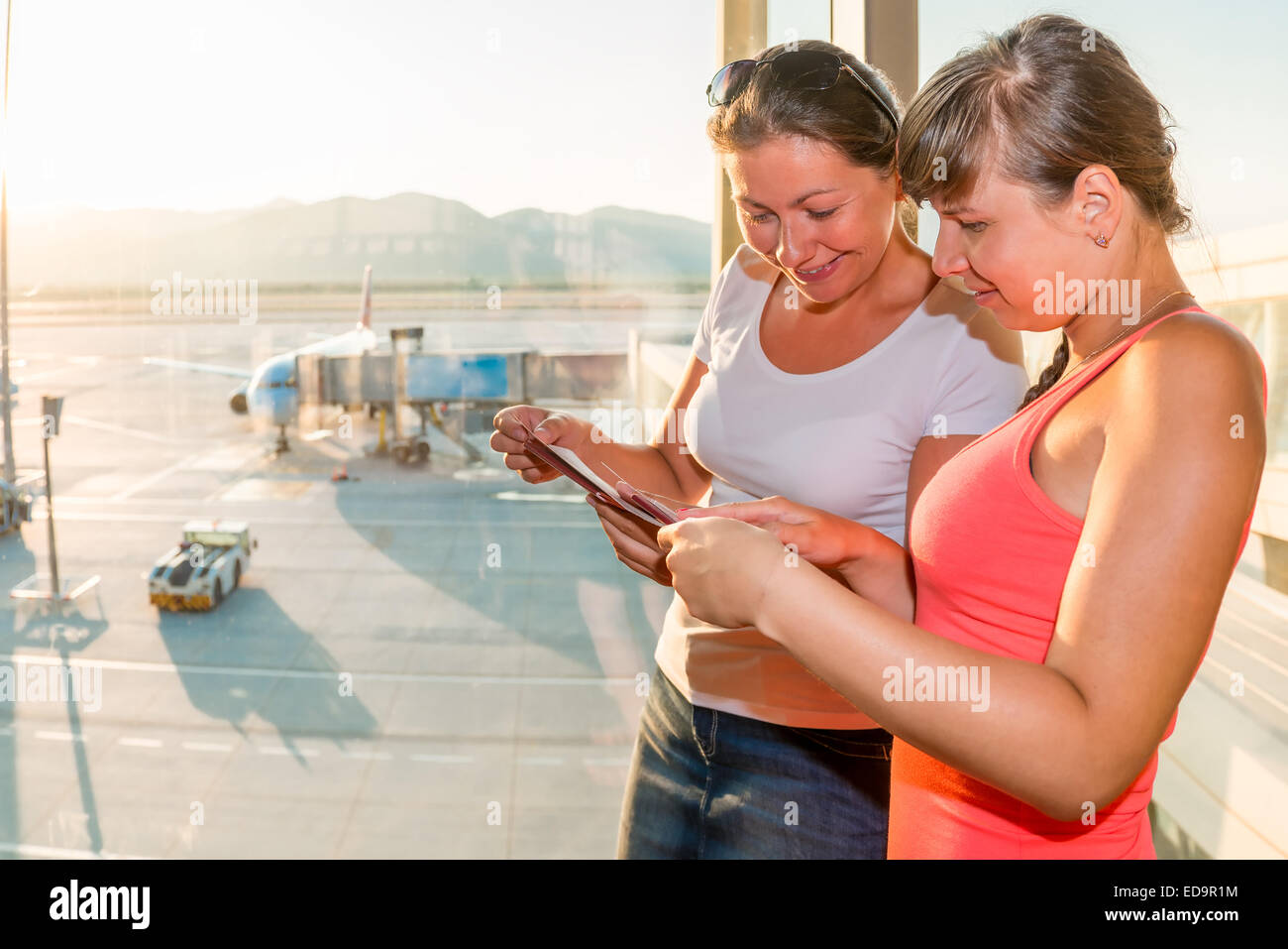 Two girls at the airport with tickets waiting for boarding Stock Photo ...