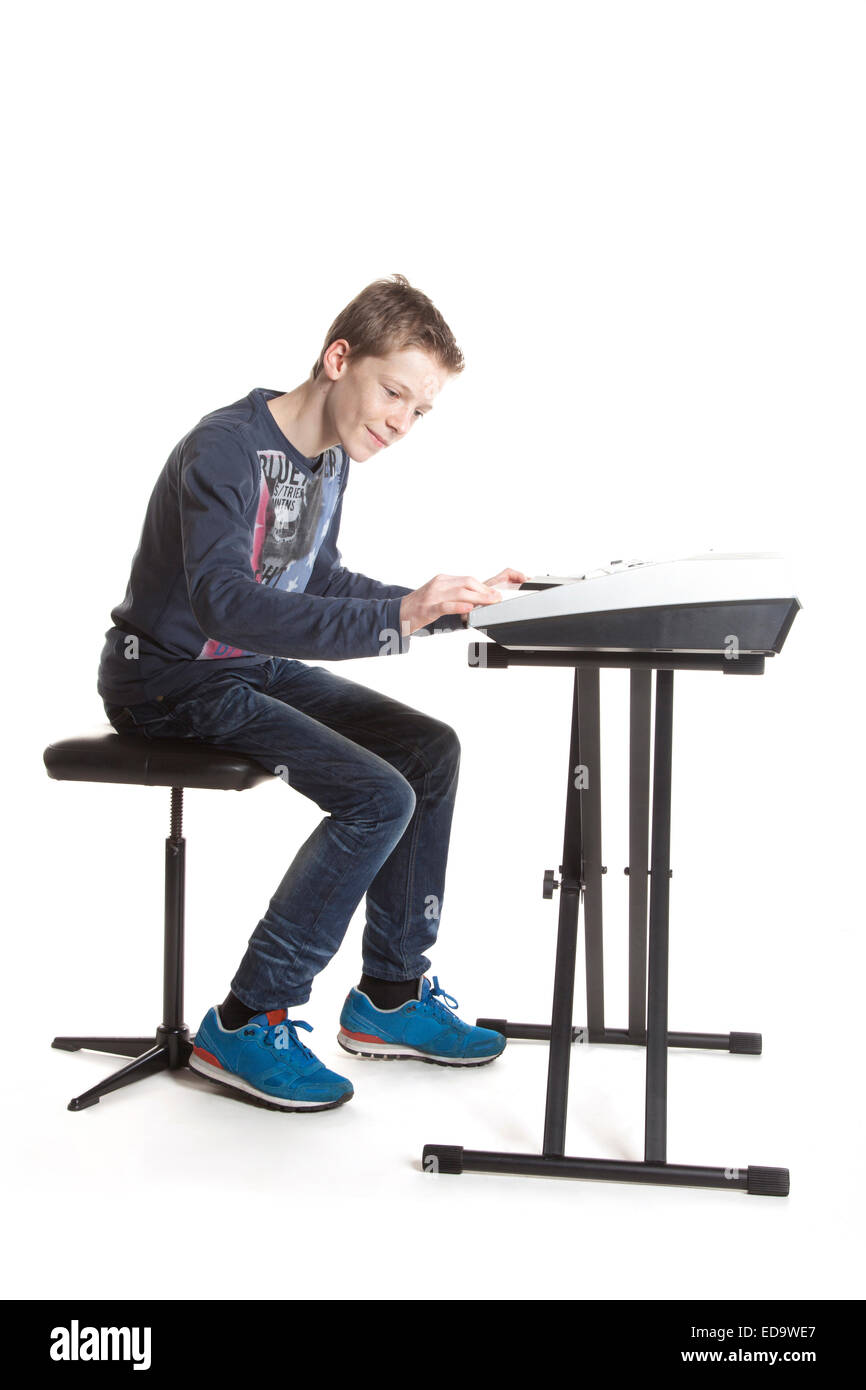 teenage boy playing on keyboard in studio against white background ...
