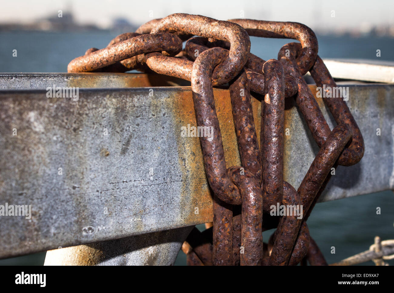 Heavy duty, rusty chains clinging onto the side of a metal barrier at ...