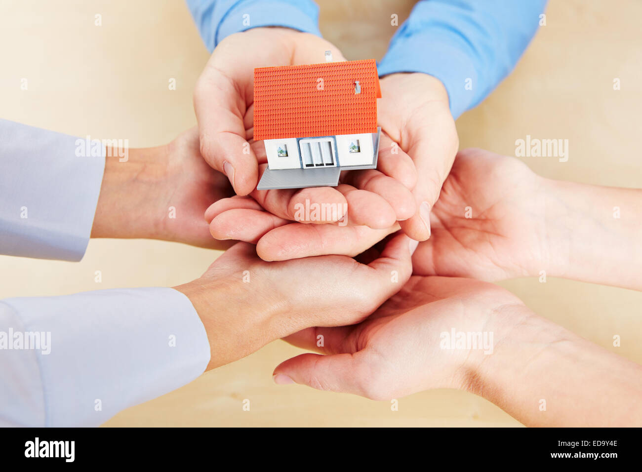 Many hands holding together a small house as concept for security and ...